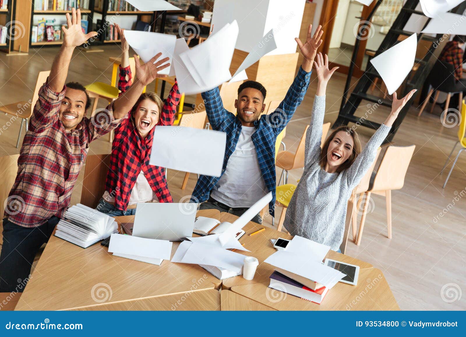 Happy Students Sitting in Library Throw Up the Paper. Stock Photo ...