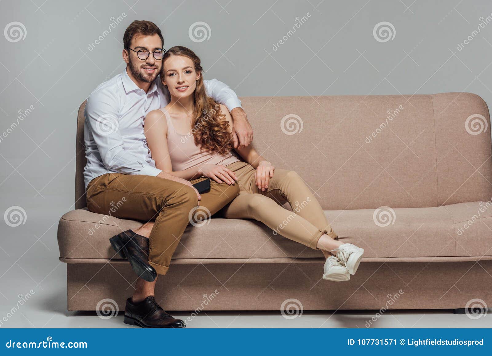 Happy Stylish Young Couple With Smartphone Smiling At Camera While