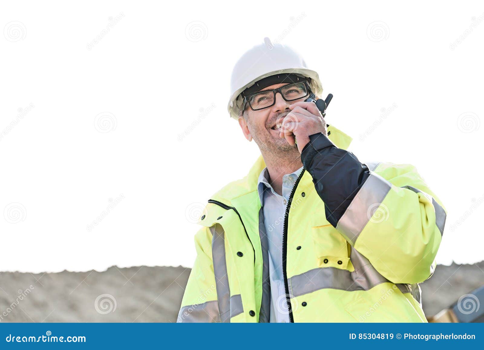 Happy Supervisor Using Walkie-talkie at Construction Site Against Clear ...
