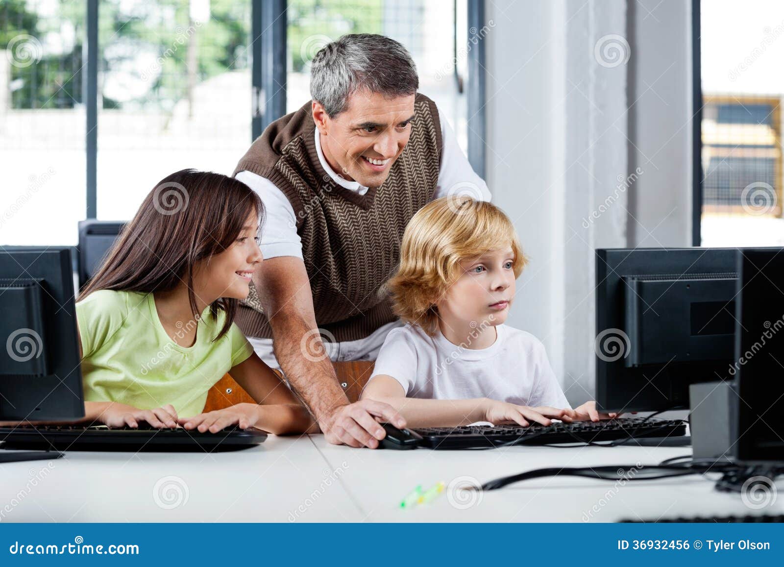 Happy Teacher Assisting Schoolchildren in Using Stock Photo - Image of ...