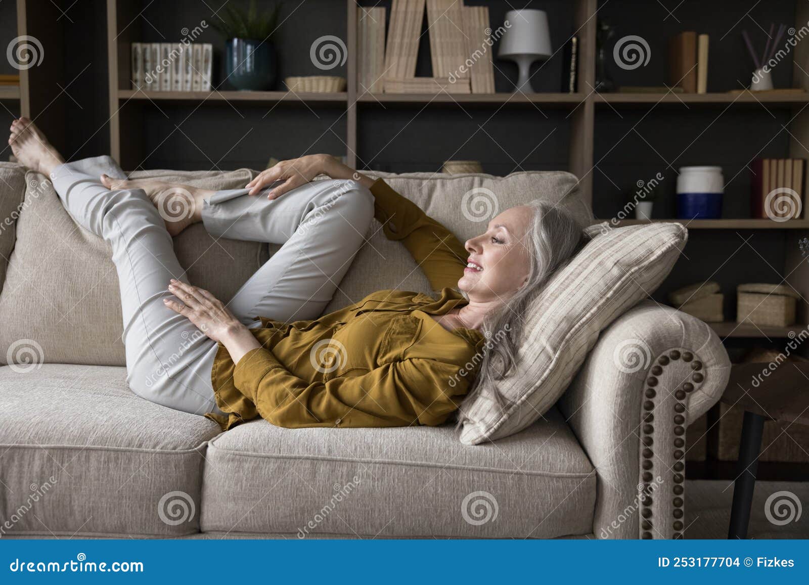 Happy Thoughtful Relaxed Grey Haired Woman Lying On Comfortable Couch