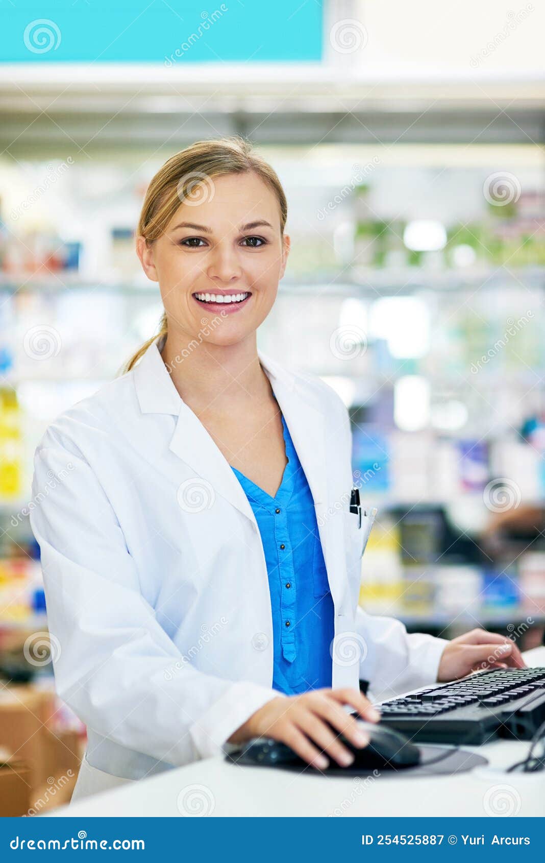 Happy To Assist You. a Young Pharmacist Using a Computer at the ...
