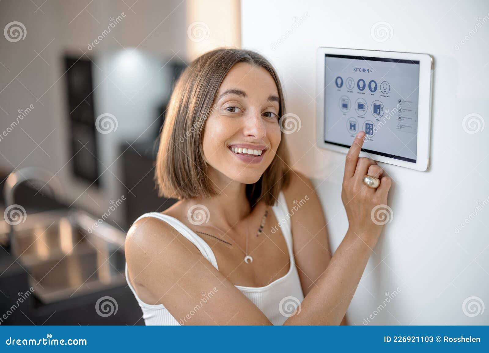 Happy Woman Controlling Smart Devices Using Control Panel at Kitchen ...