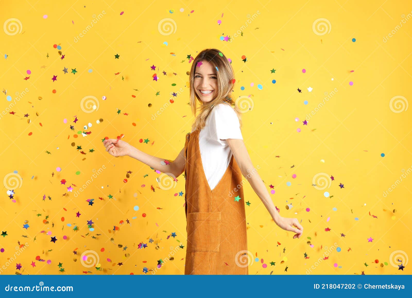 Happy Woman and Falling Confetti on Yellow Background Stock Photo ...