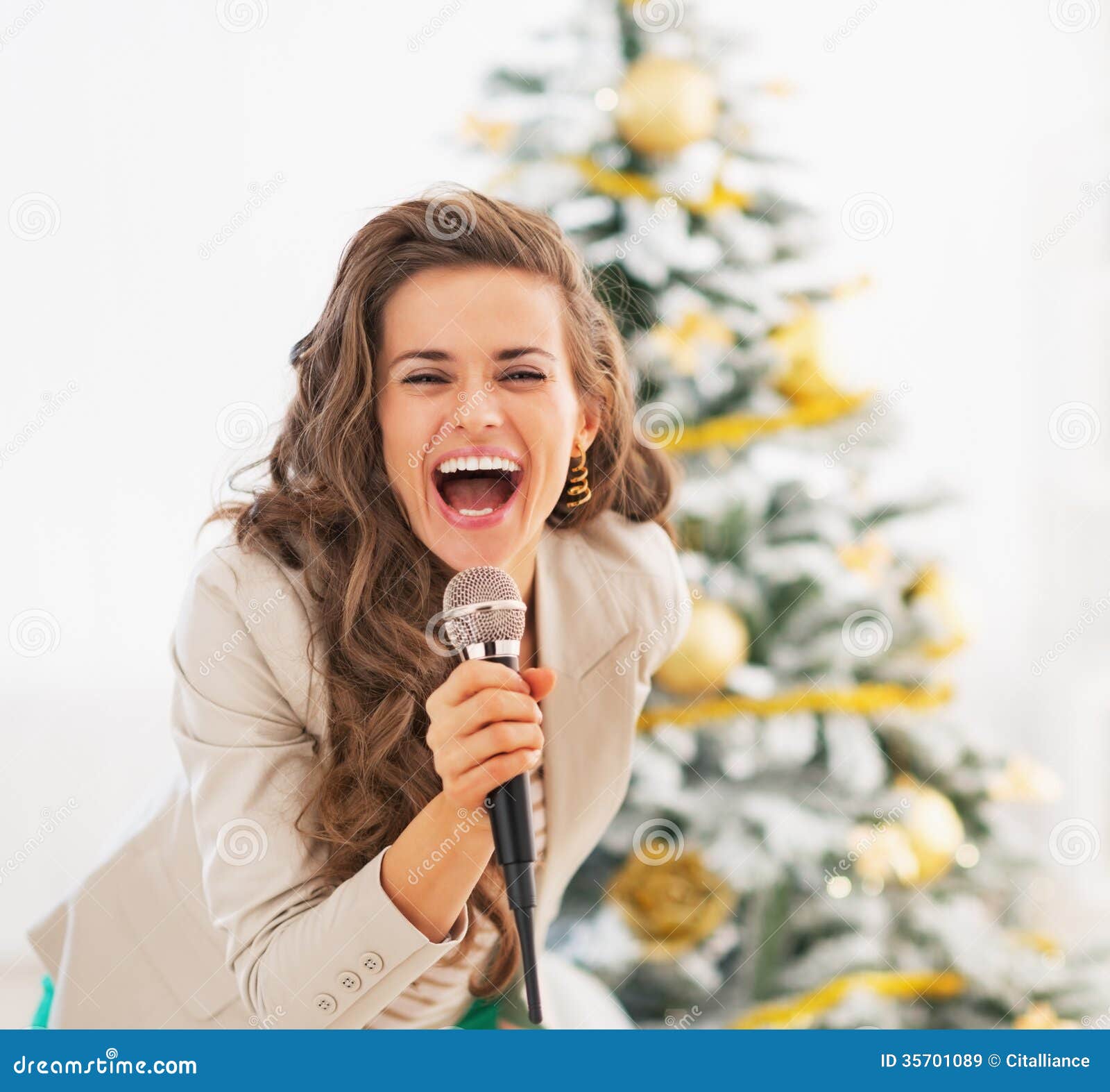 Happy Woman Singing with Microphone in Front of Christmas Tree Stock ...