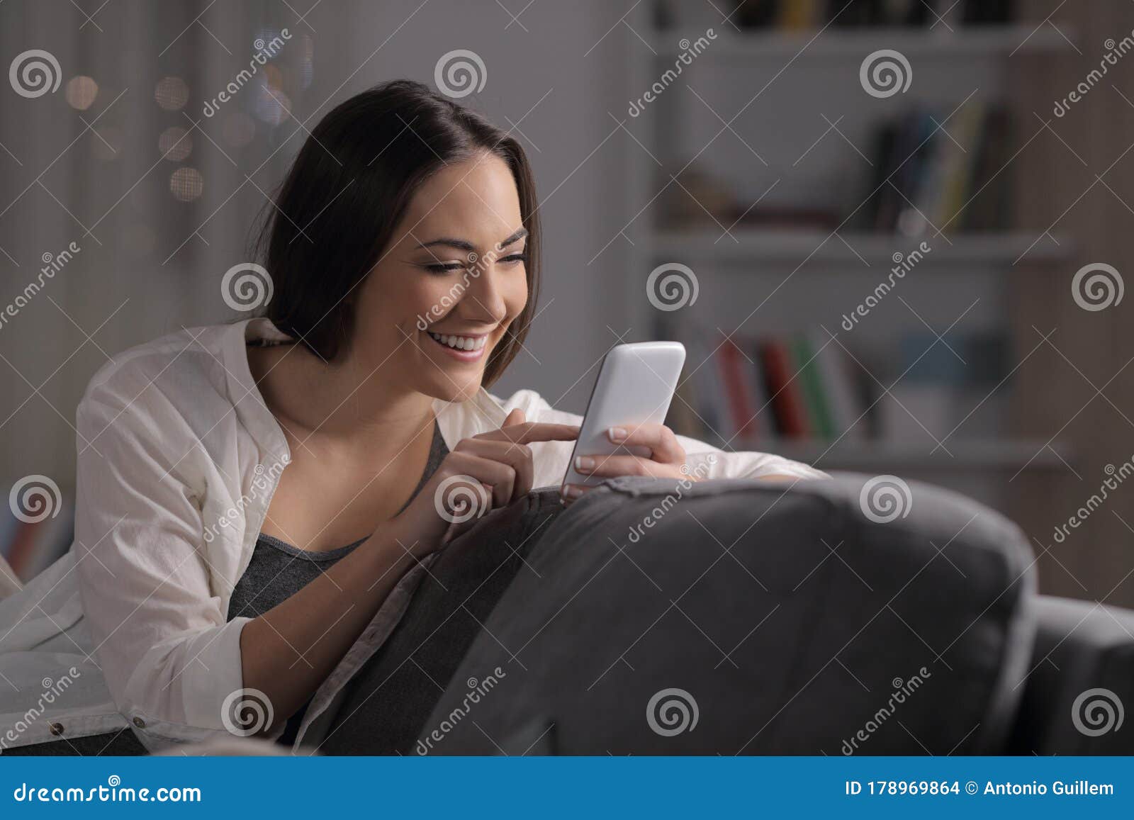 Happy Woman Using Phone in the Night on a Couch Stock Photo - Image of ...