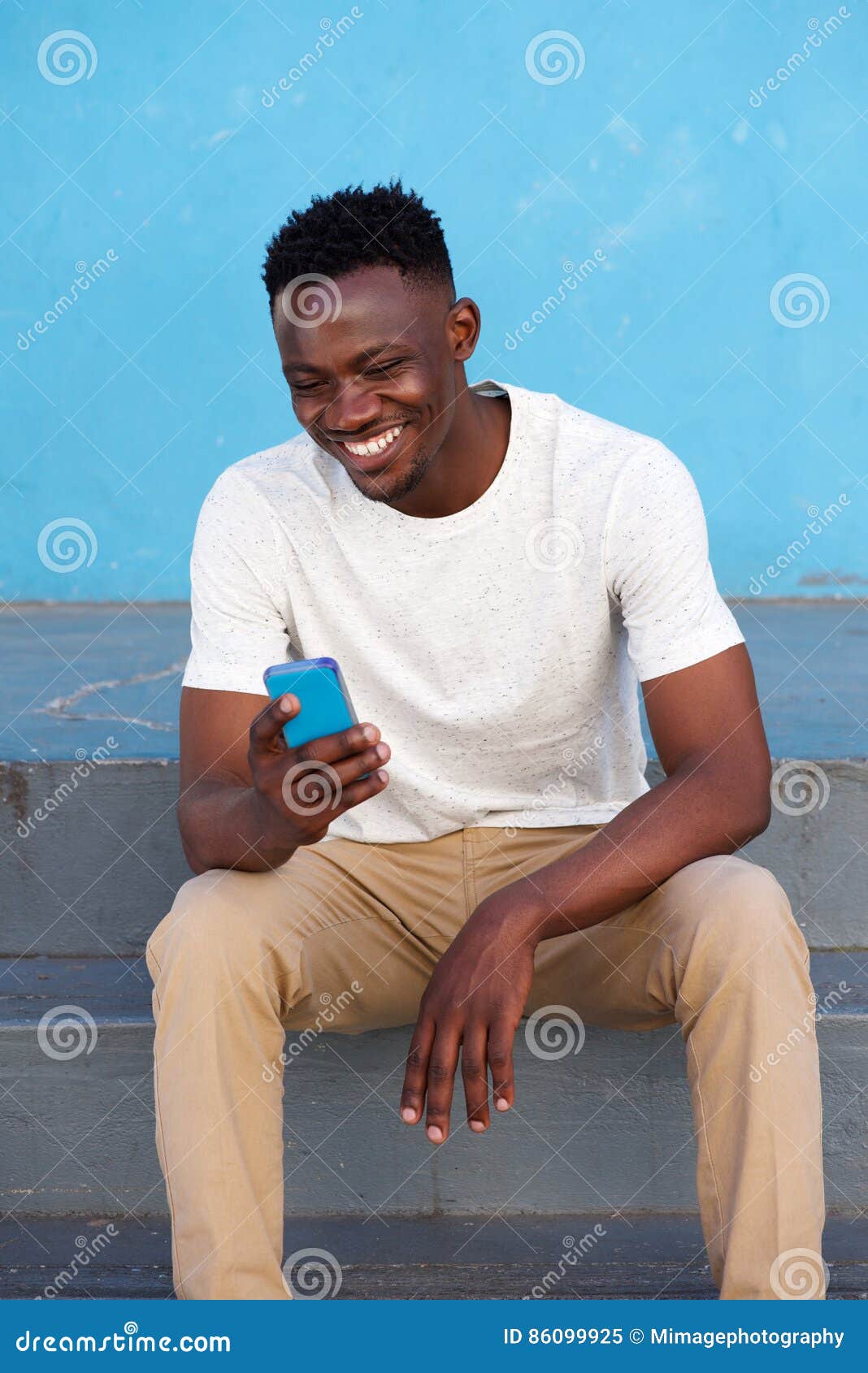 Happy Young African Man Sitting on Steps and Using Phone Stock Image ...