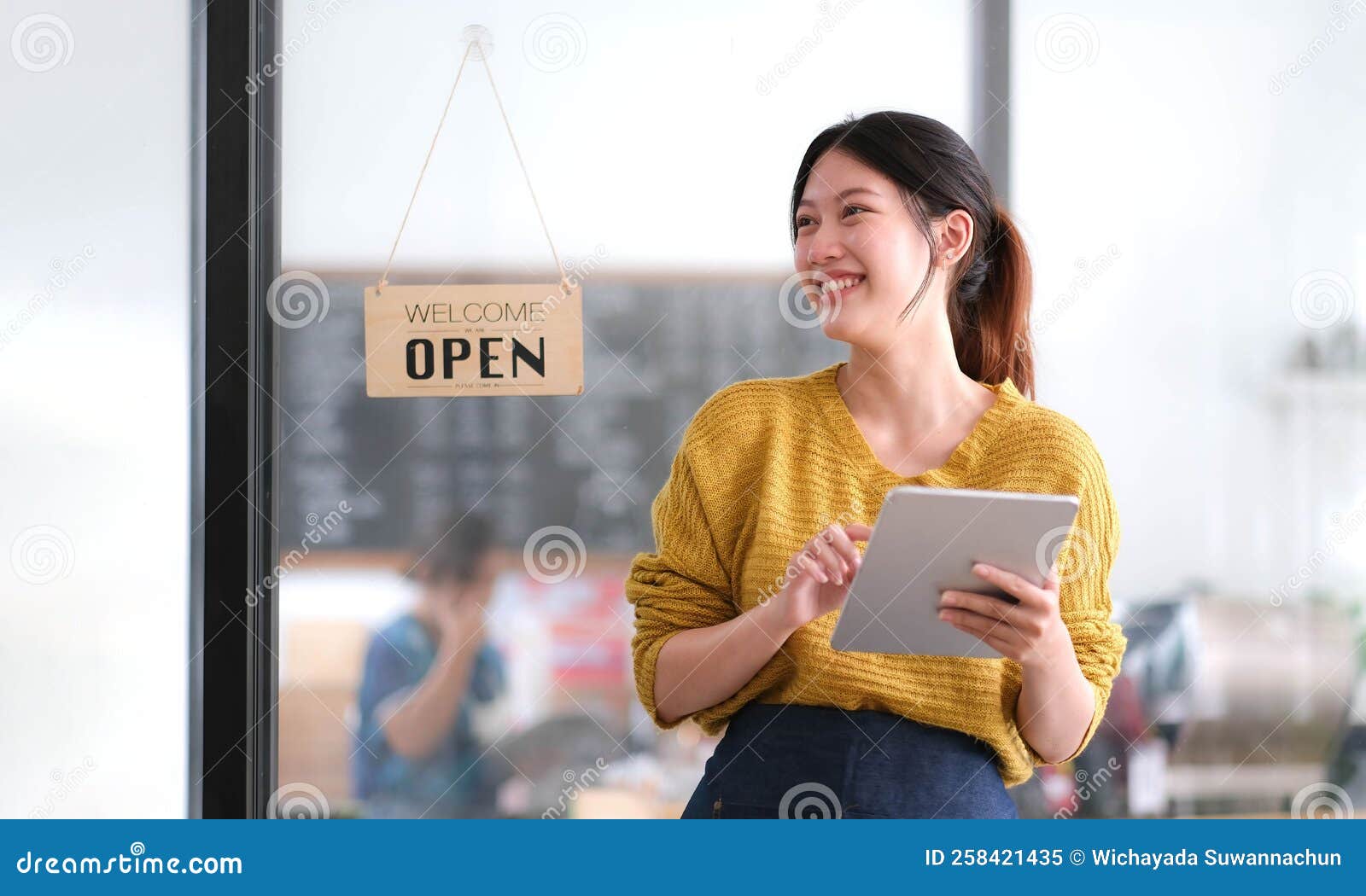 Happy Young Asian Woman Owner Standing Holding a Tablet with Open Sign ... Happy Young Asian Woman Owner Standing Holding a Tablet with Open Sign ...