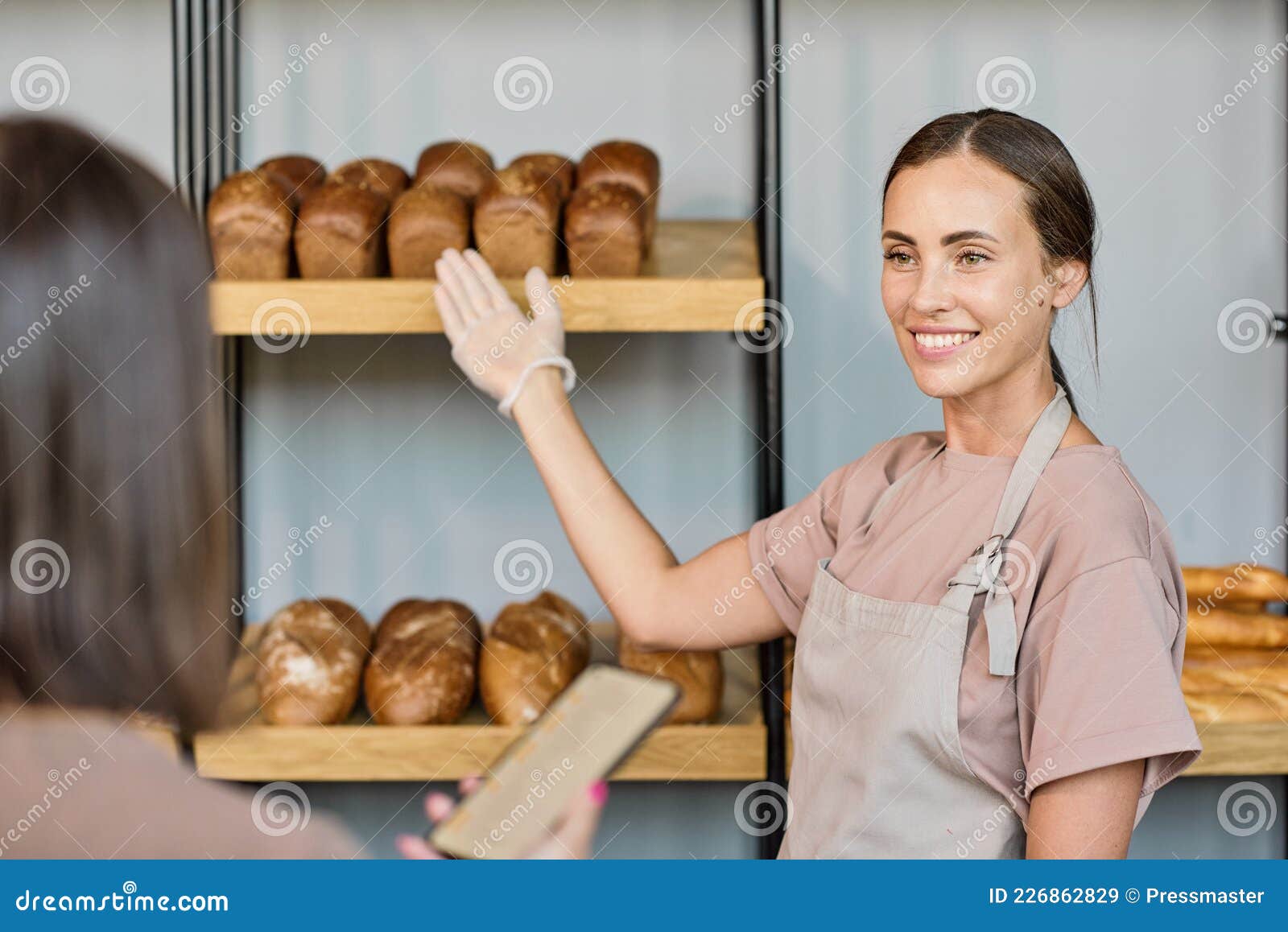 Happy Young Bakery Worker Serving Female Customer with Smartphone Stock ...