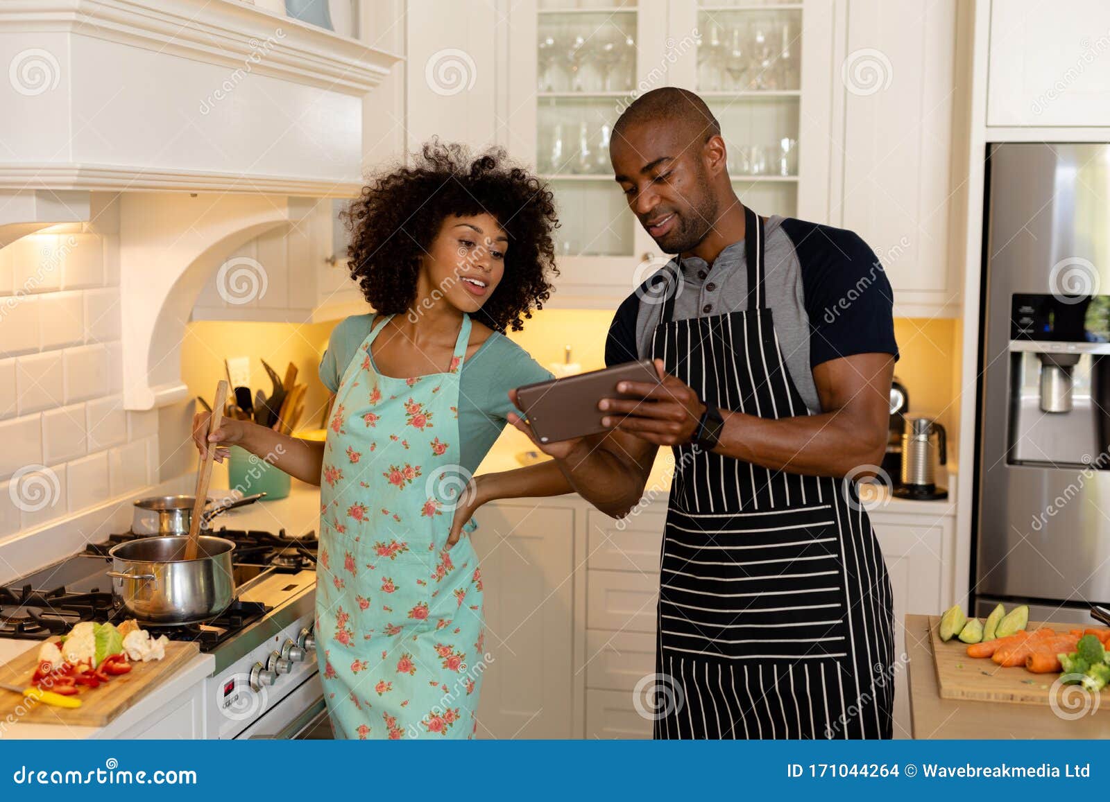 Happy Young Couple Cooking and Using Tablet Computer in the Kitchen ...