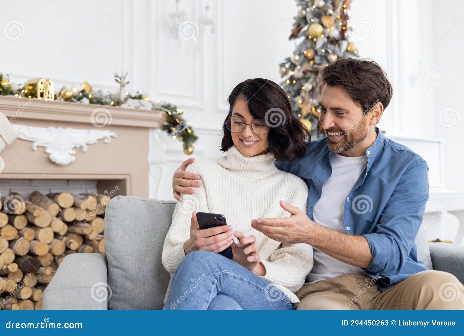 Happy Young Couple Man And Woman Sitting On Sofa Together Hugging And