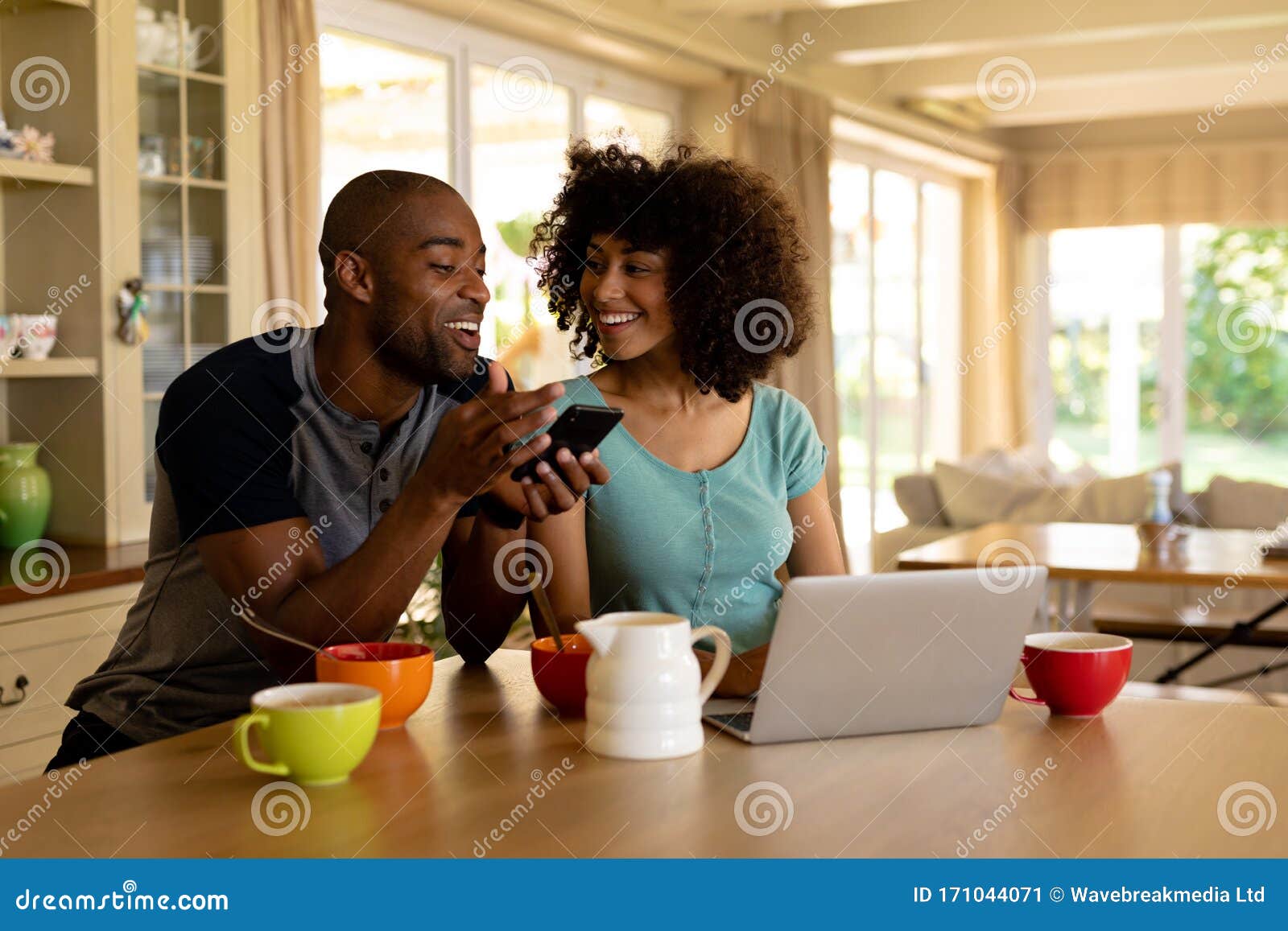 Happy Young Couple Using Computer and Mobile Phone in the Kitchen Stock ...