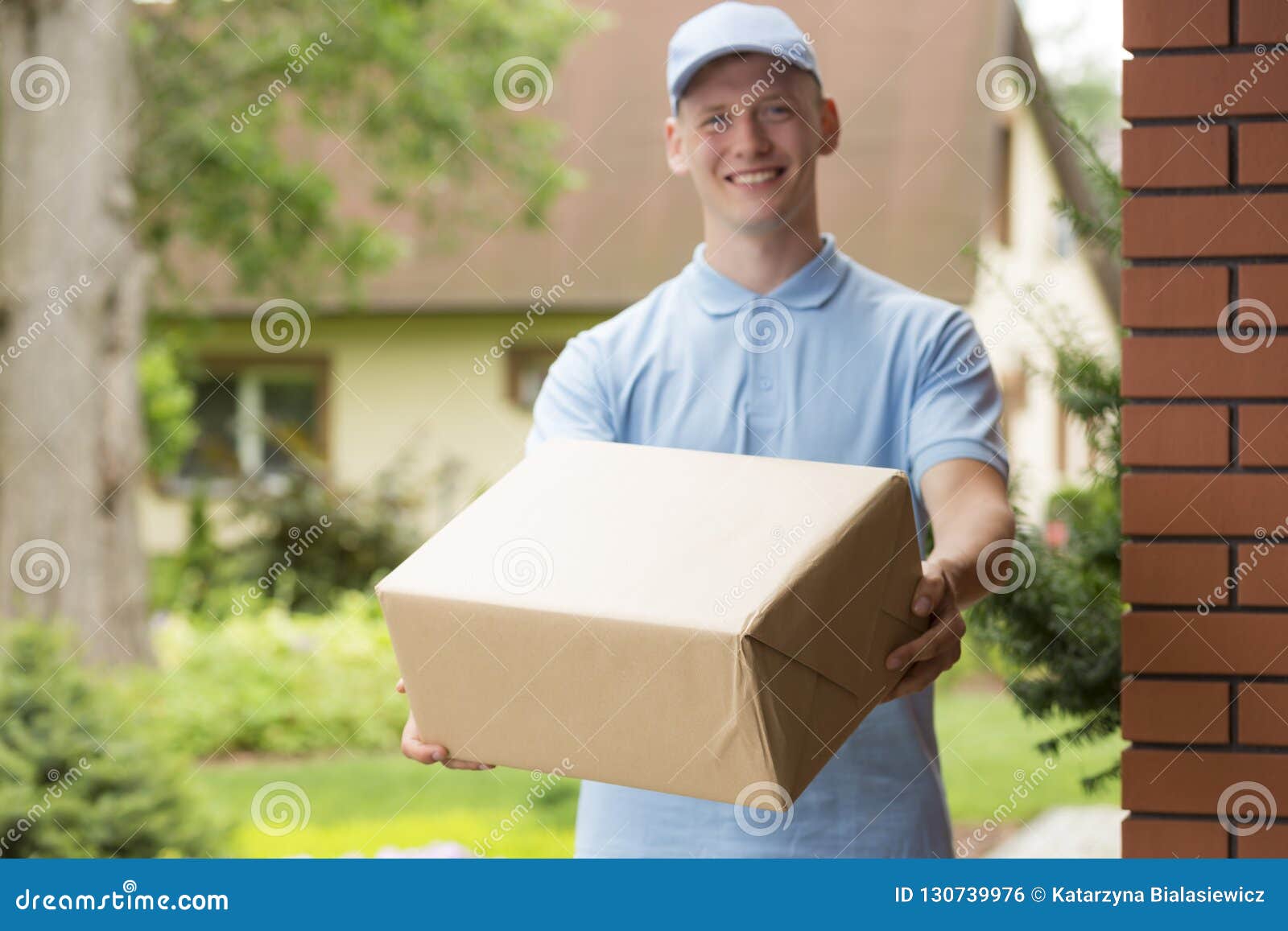Young Courier in Blue Uniform Holding a Package Stock Photo - Image of ...
