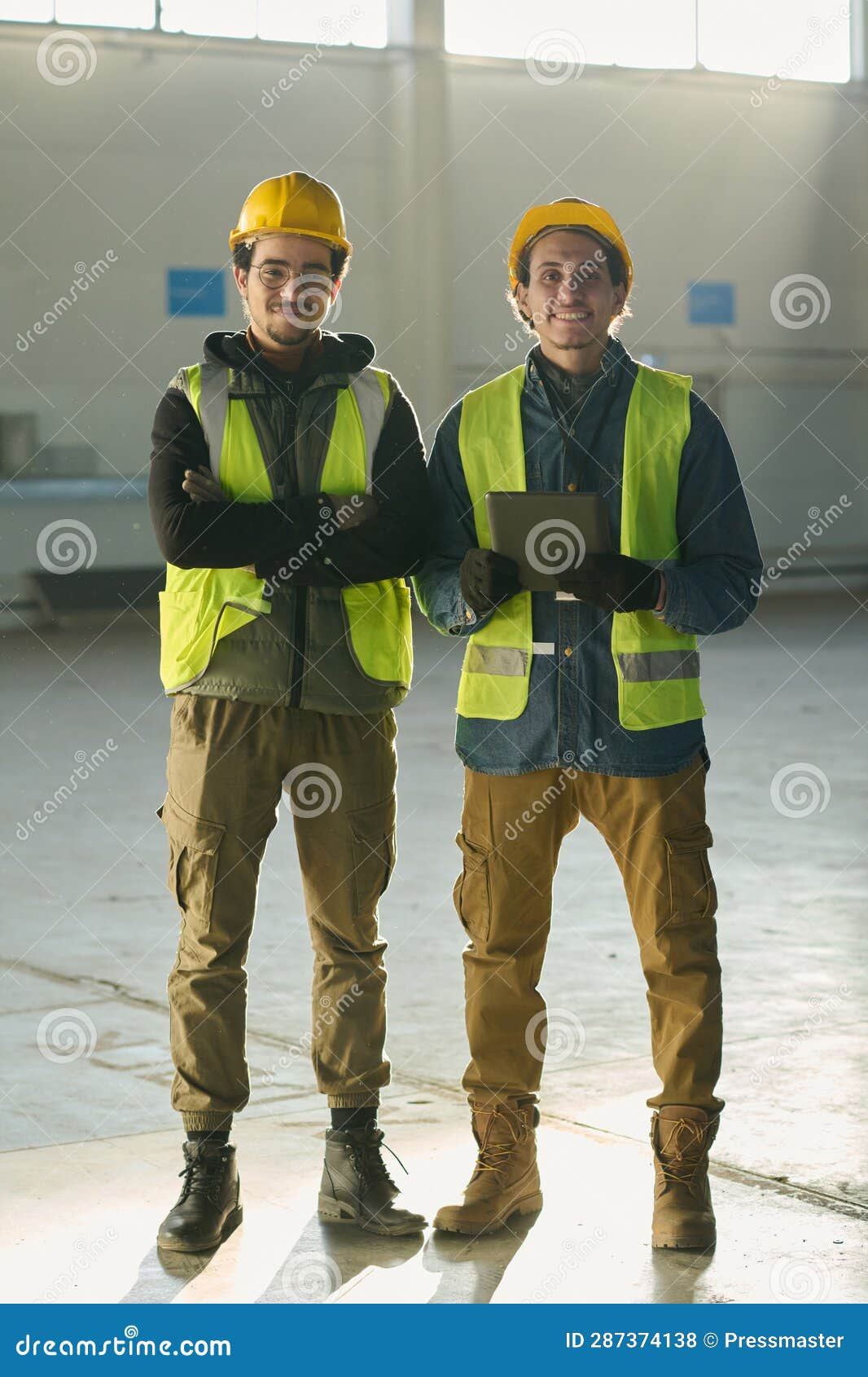 Happy Young Male Colleagues in Safety Helmets and Reflective Jackets ...