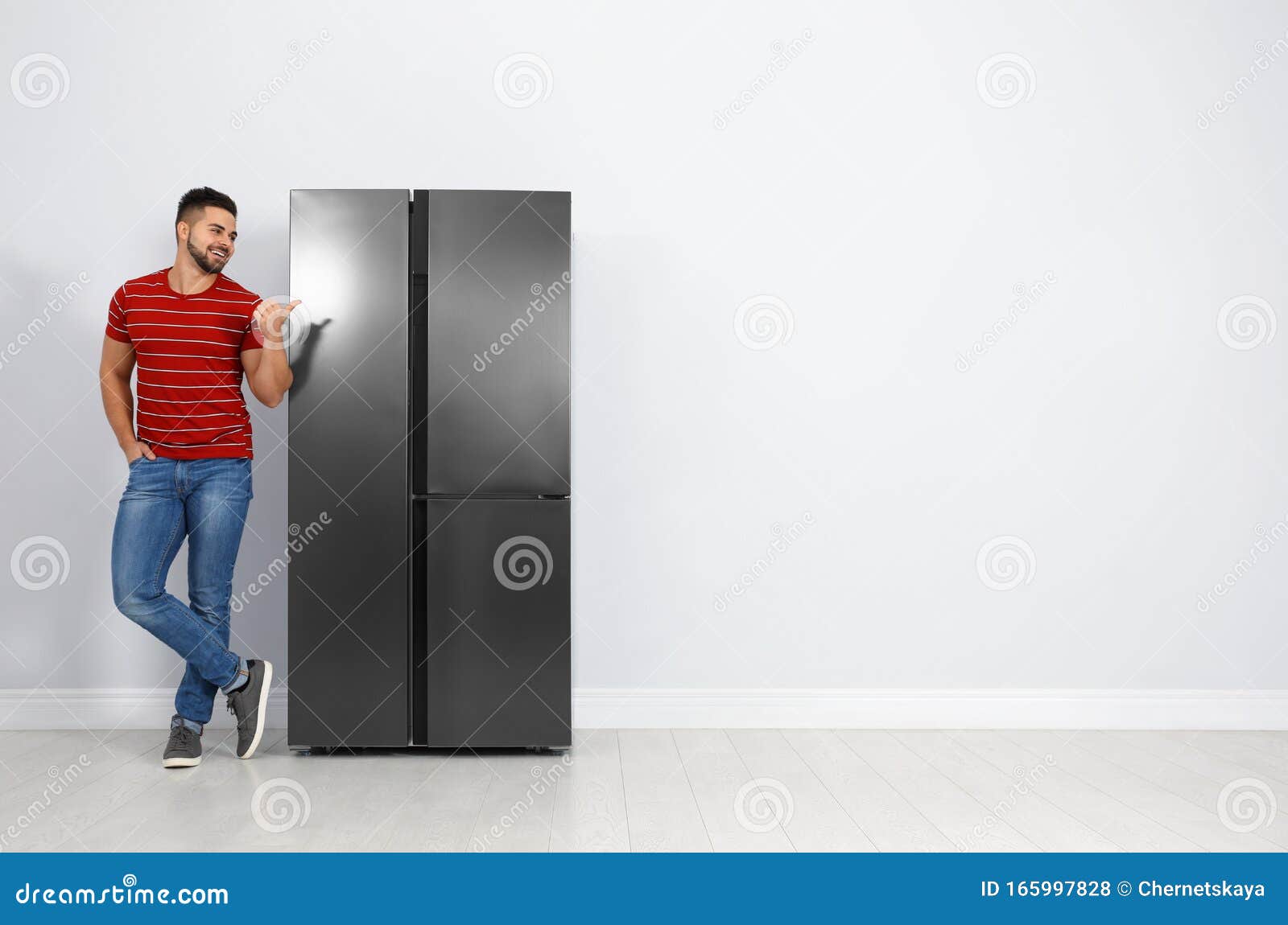 Happy Young Man Near Refrigerator Indoors, Space for Text Stock Photo ...