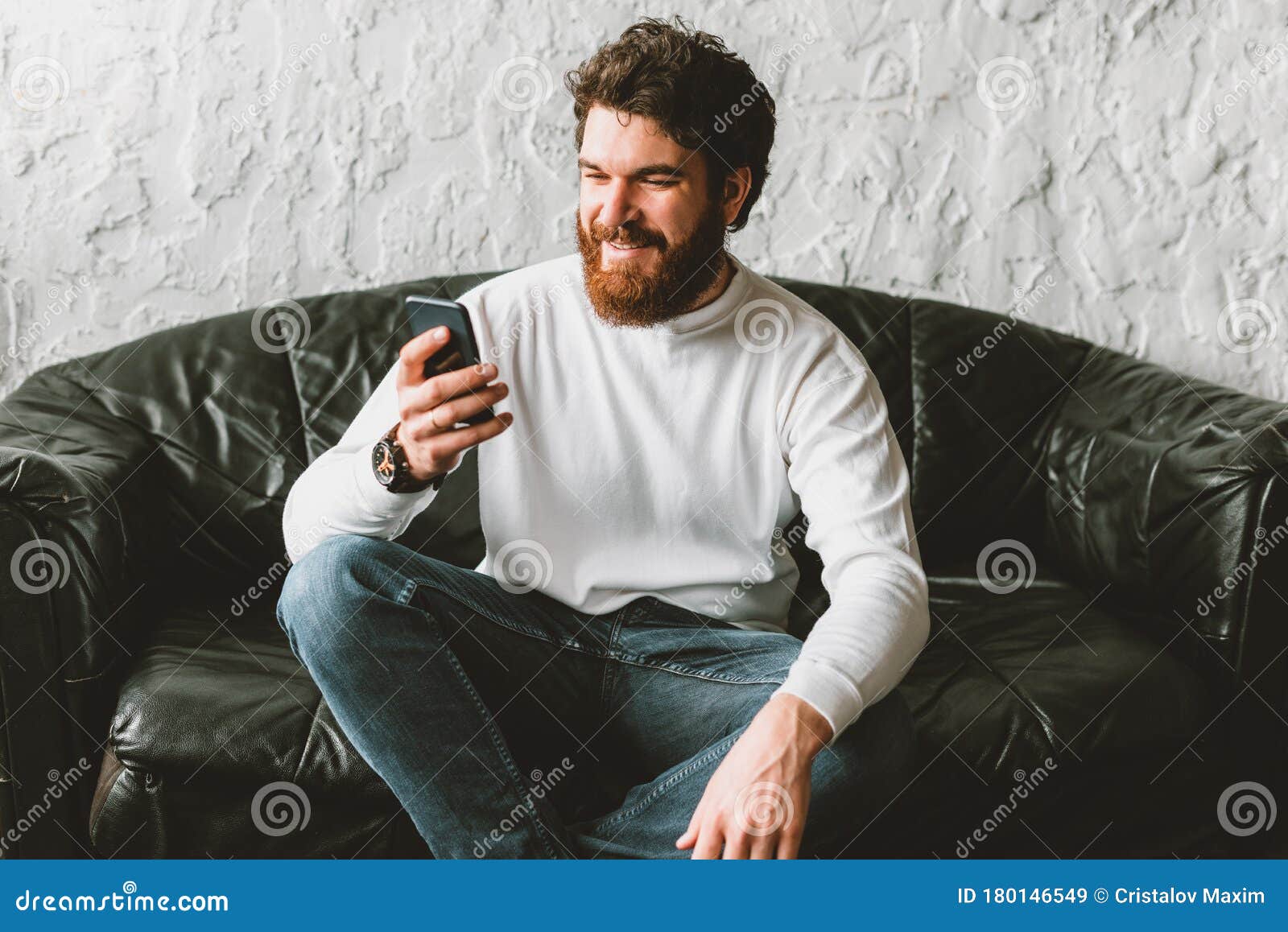 Happy Young Man Using His Smartphone and Sitting on Sofa Stock Image ...