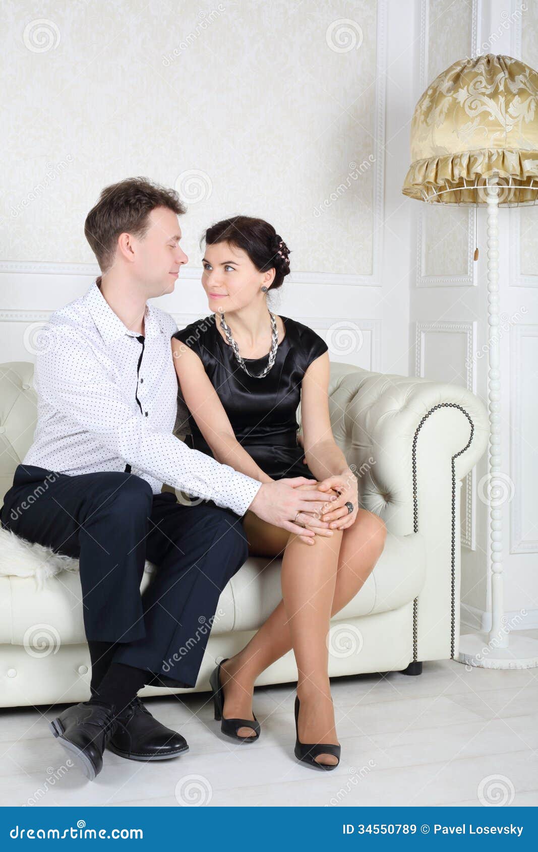 Happy Young Man And Woman Sit At Sofa And Look At Each Other Stock