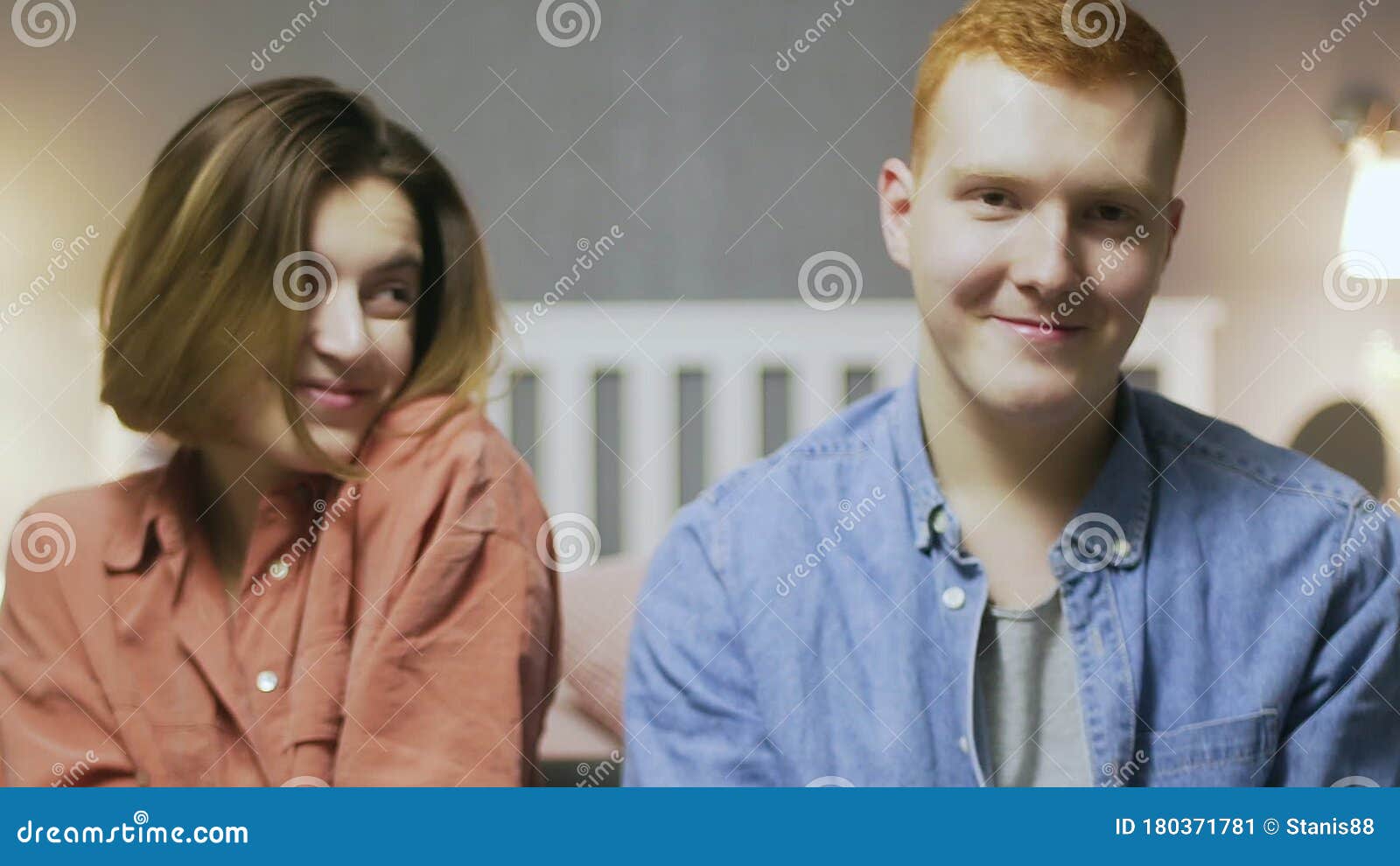 Happy Young Man And Woman Sitting On The Sofa Looking At The Camera And