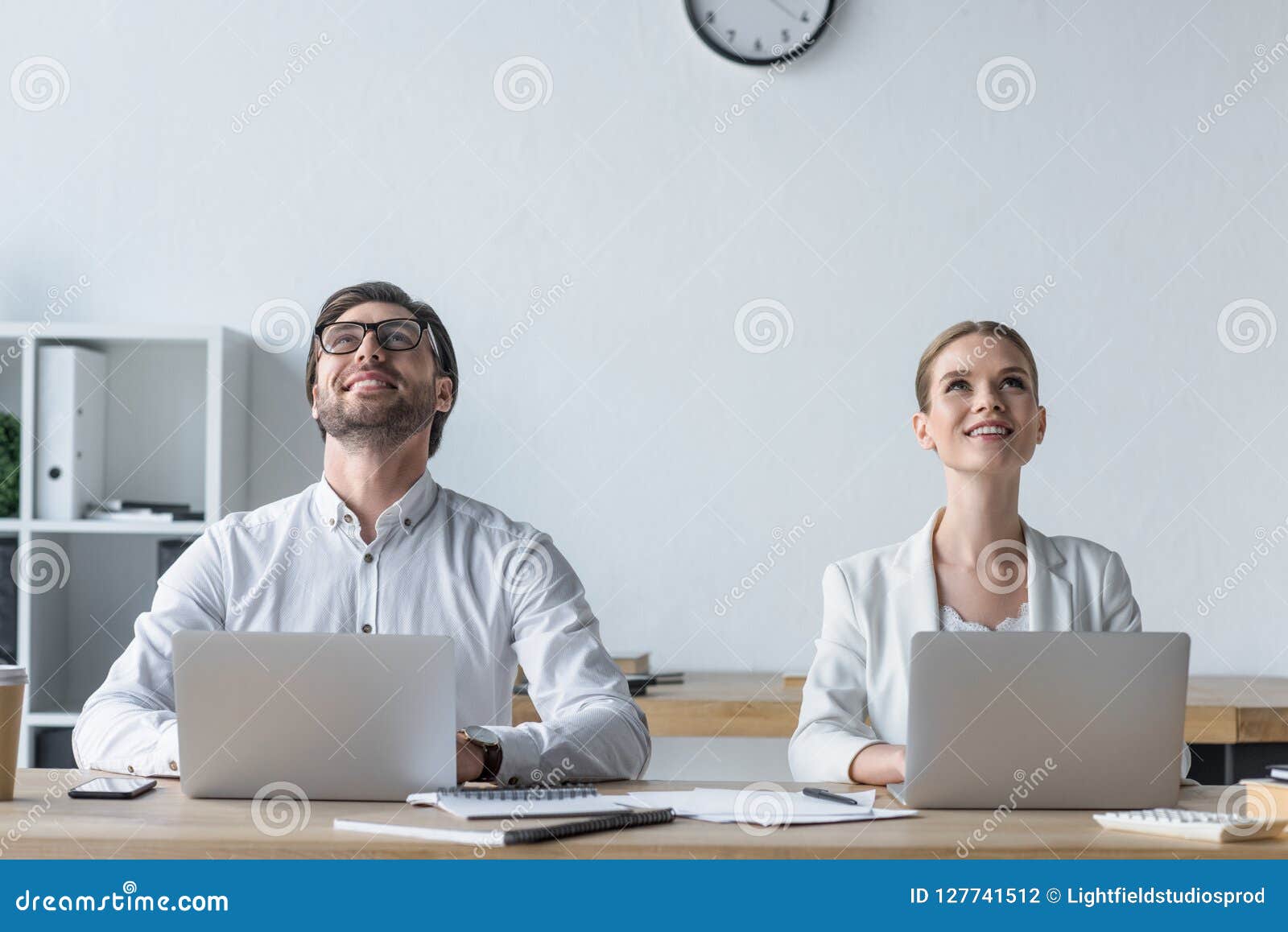 Happy Young Managers Working with Laptops Together and Looking Up Stock ...