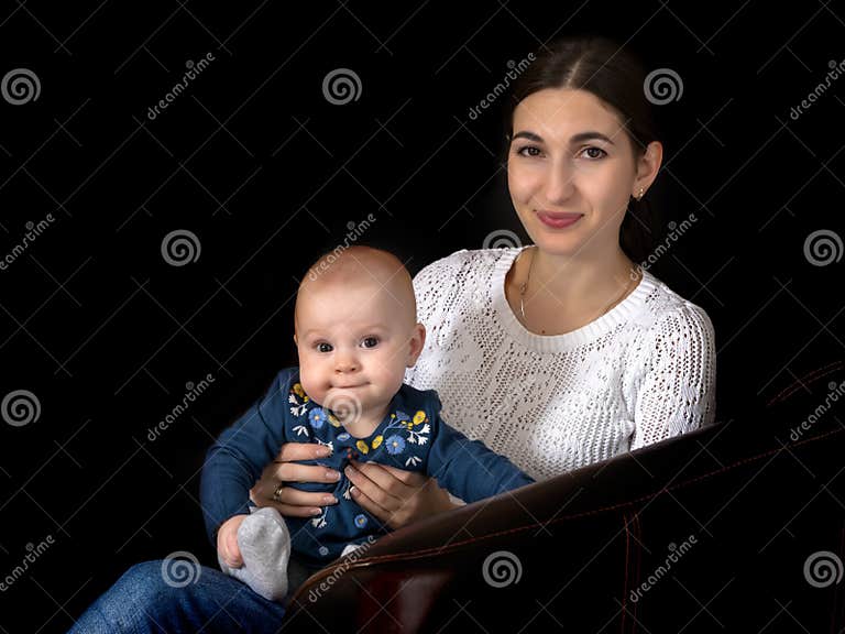 Happy Young Mother With Her Daughter On Her Hands On A Black Bac Stock