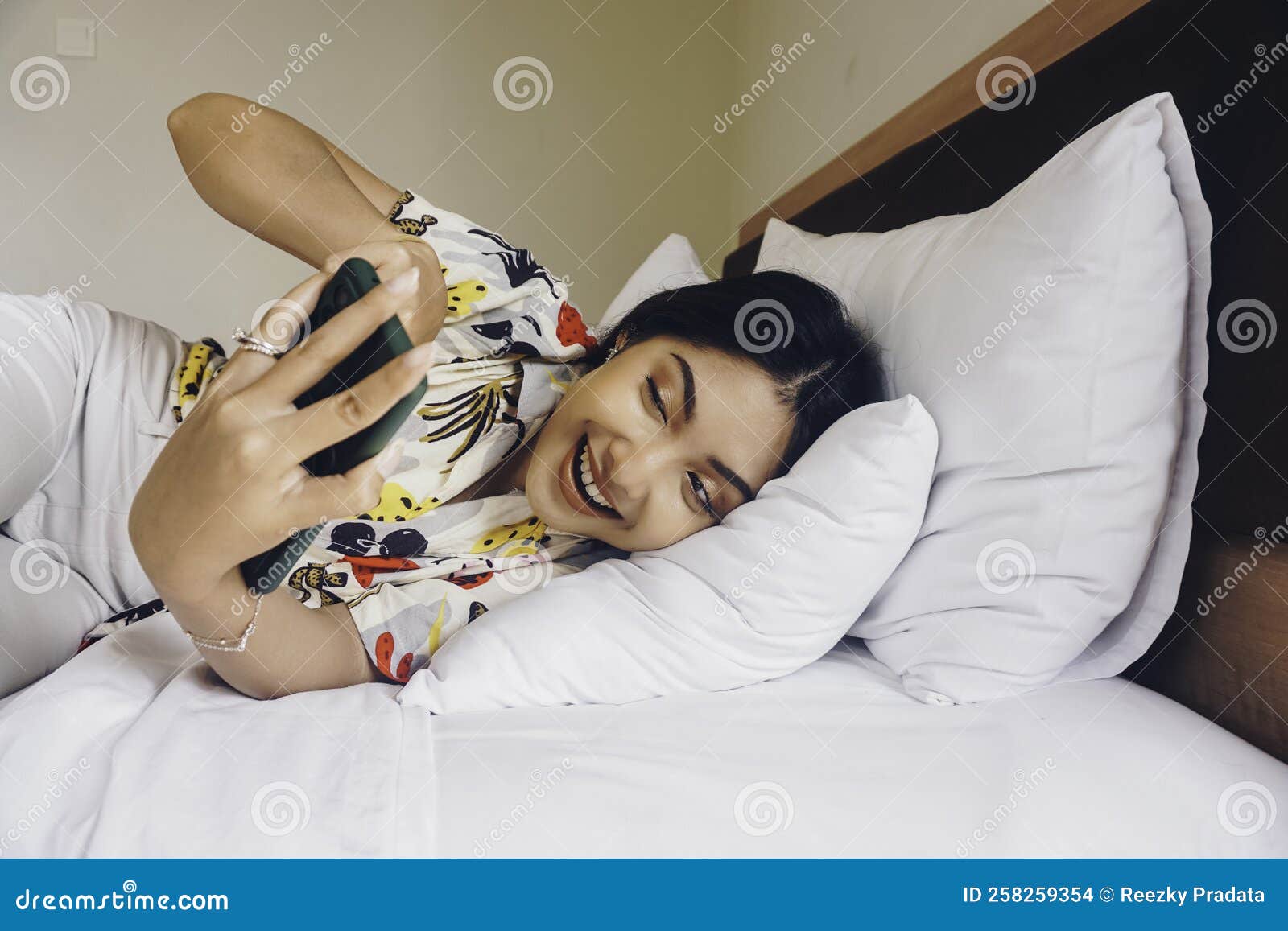 Happy Young Woman Checking on Her Phone while Lying in Bed Stock Photo ...