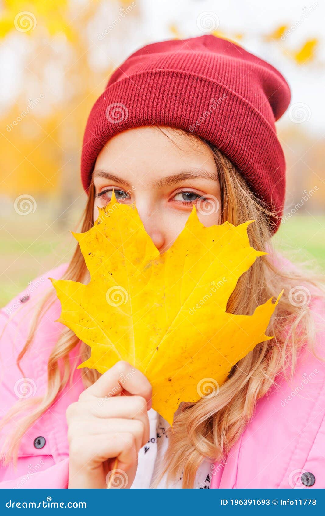 Happy Young Woman Playing With Falling Yellow Leaves In Beautiful