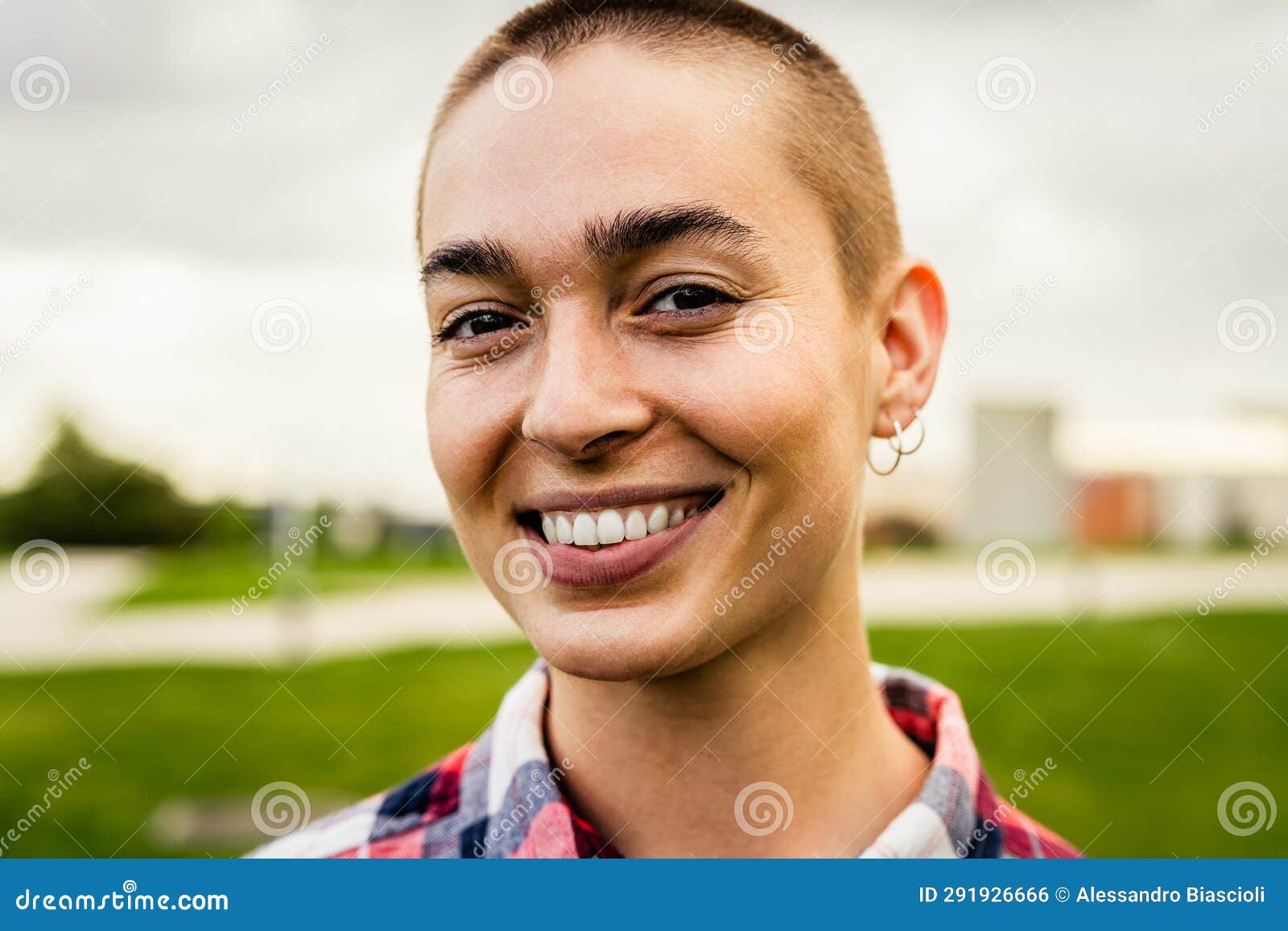 Happy Young Woman With Shaved Head Posing And Smiling In Front Camera