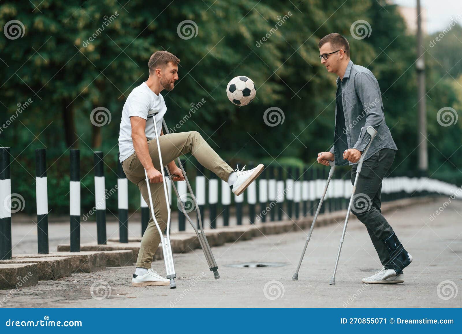 Having Fun, Playing Soccer. Two Men with Crutches is Outdoors on the ...