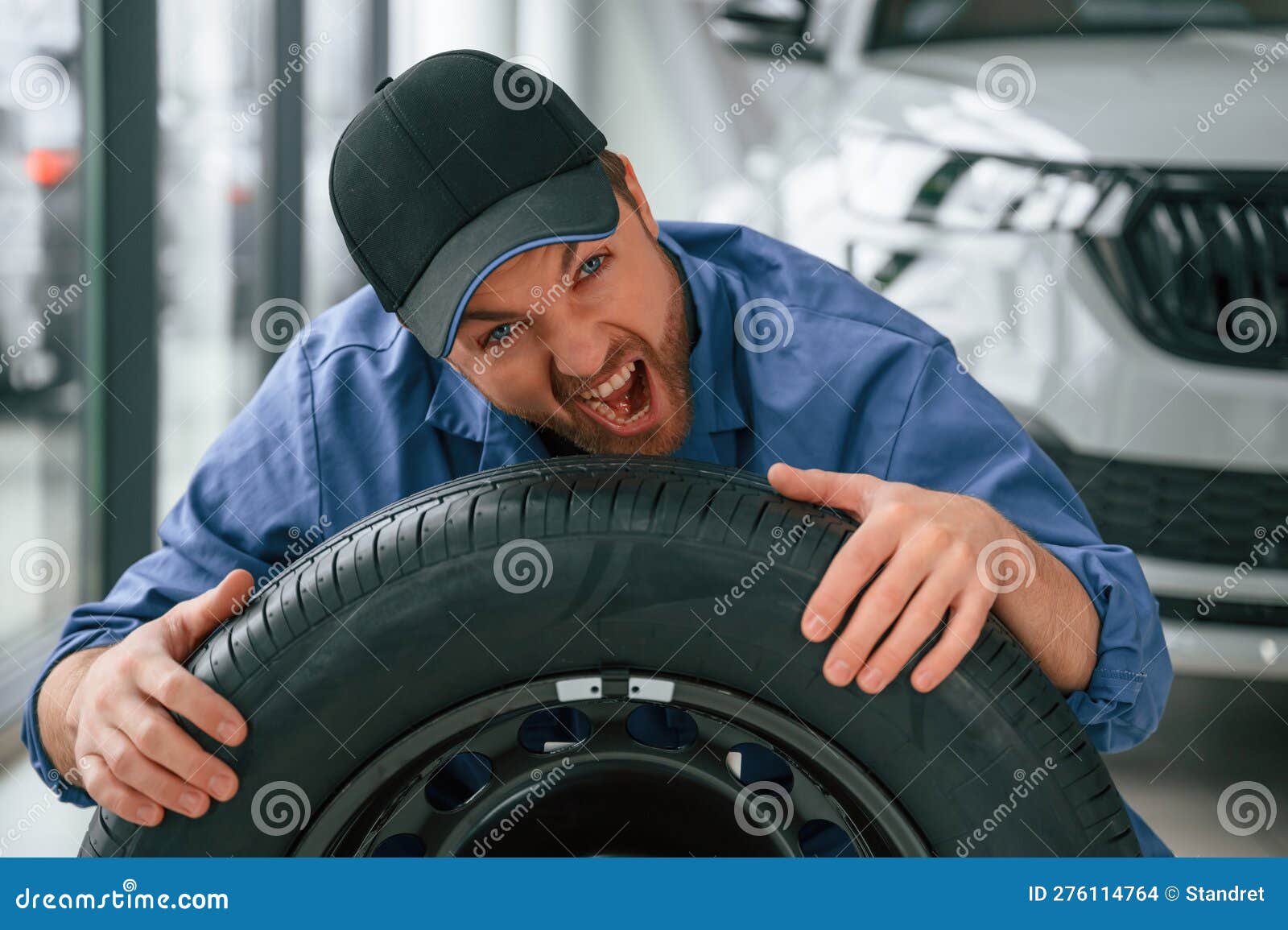 Having Fun, Smiling, with Tire. Man in Blue Uniform is Working in the ...