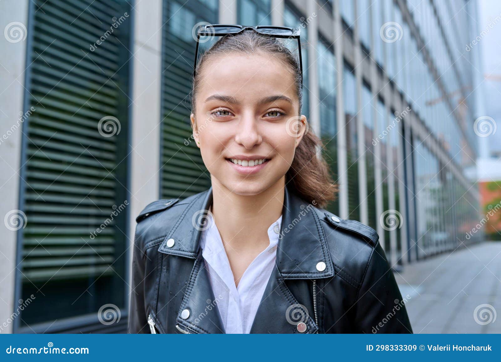 Headshot Portrait Of Teenage Girl Looking At Camera Outdoors On City