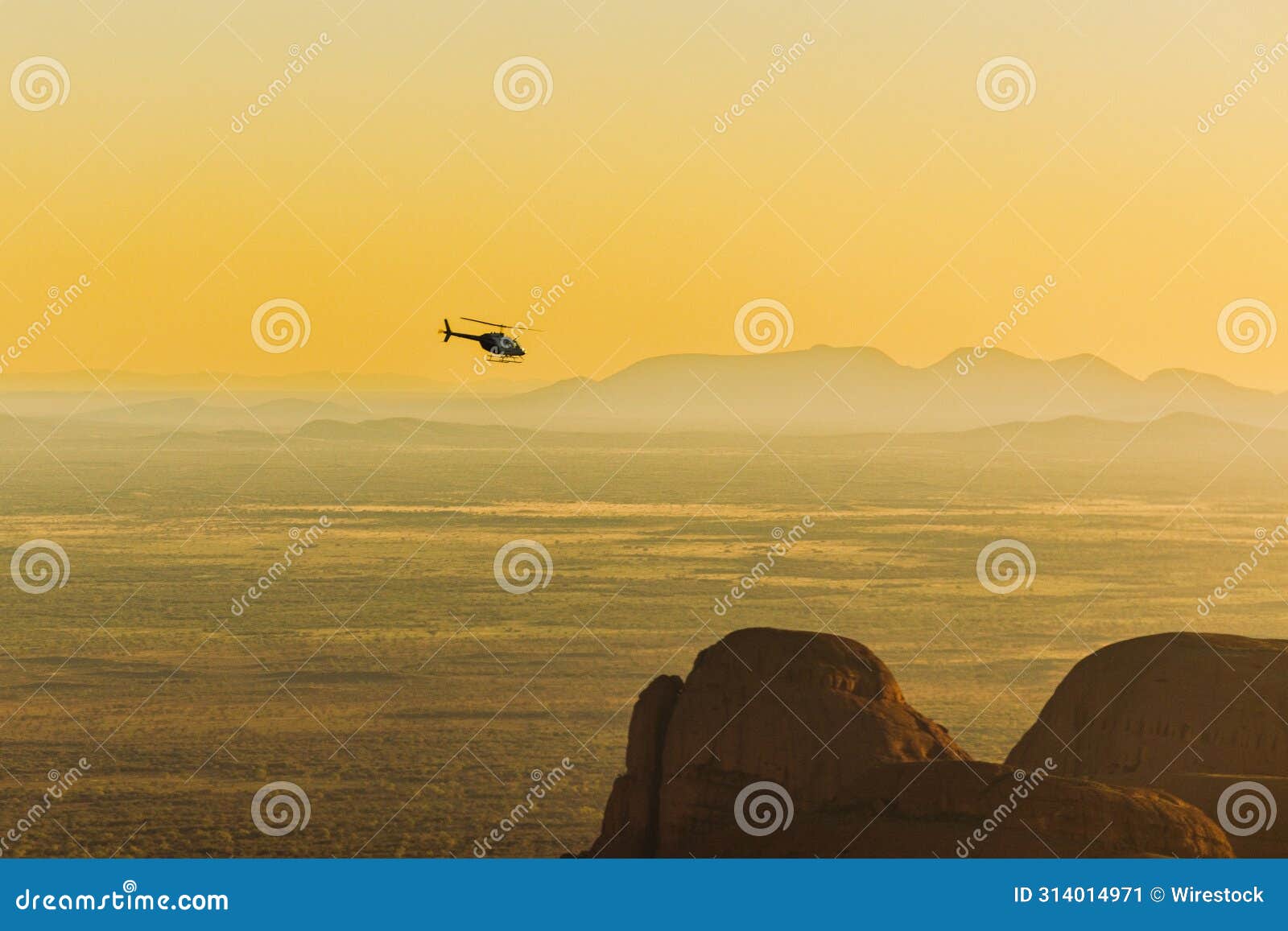 Helicopter Hovering Above a Valley with Rolling Hills and Open Plains ...