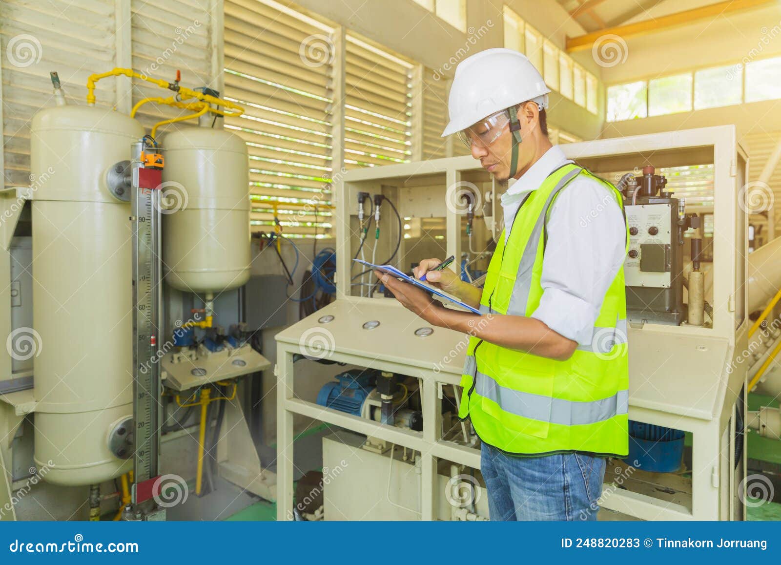A Helmeted Technician Holds a Clipboard while Checking and Taking Notes ...