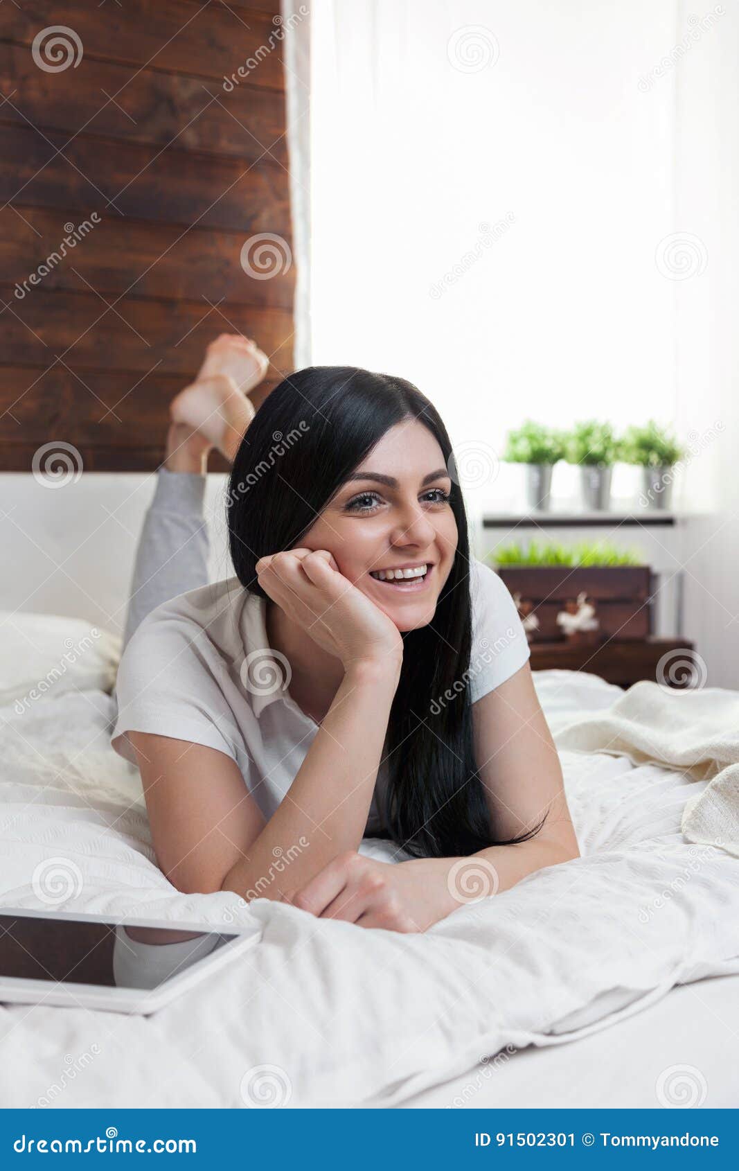 Het Mooie Vrouw Ontspannen Op Het Bed En Het Gebruiken Van Haar Tablet ... Het Mooie Vrouw Ontspannen Op Het Bed En Het Gebruiken Van Haar Tablet ...