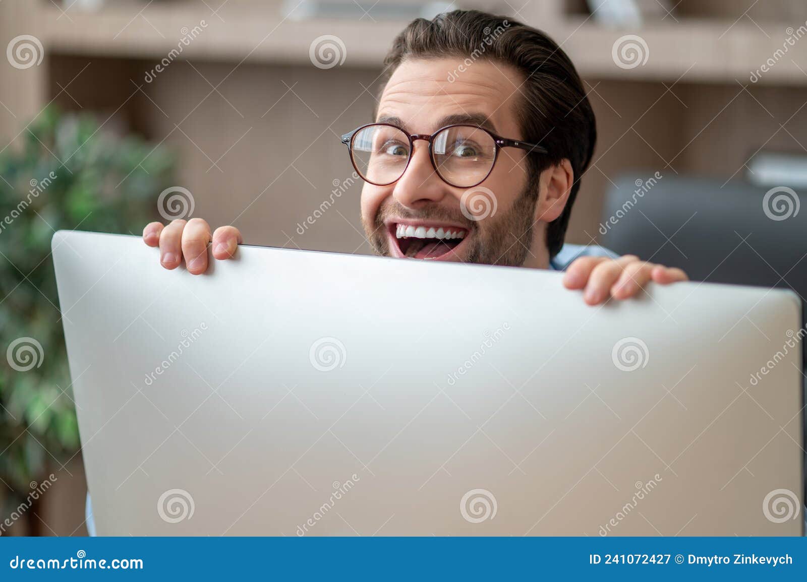 A Dark-haired Man Hiding Behind the Computer and Smiling Stock Image ...