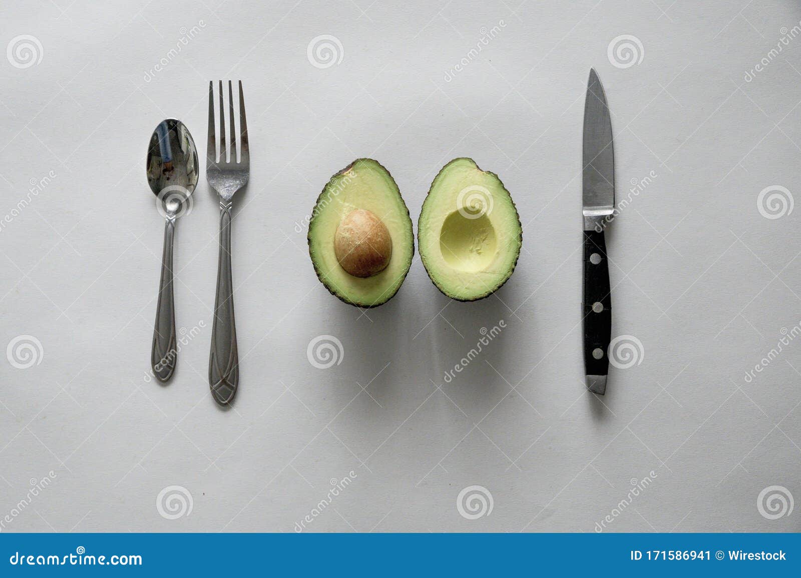 High Angle Shot of an Avocado, a Knife and Spoon and Fork on a White ...