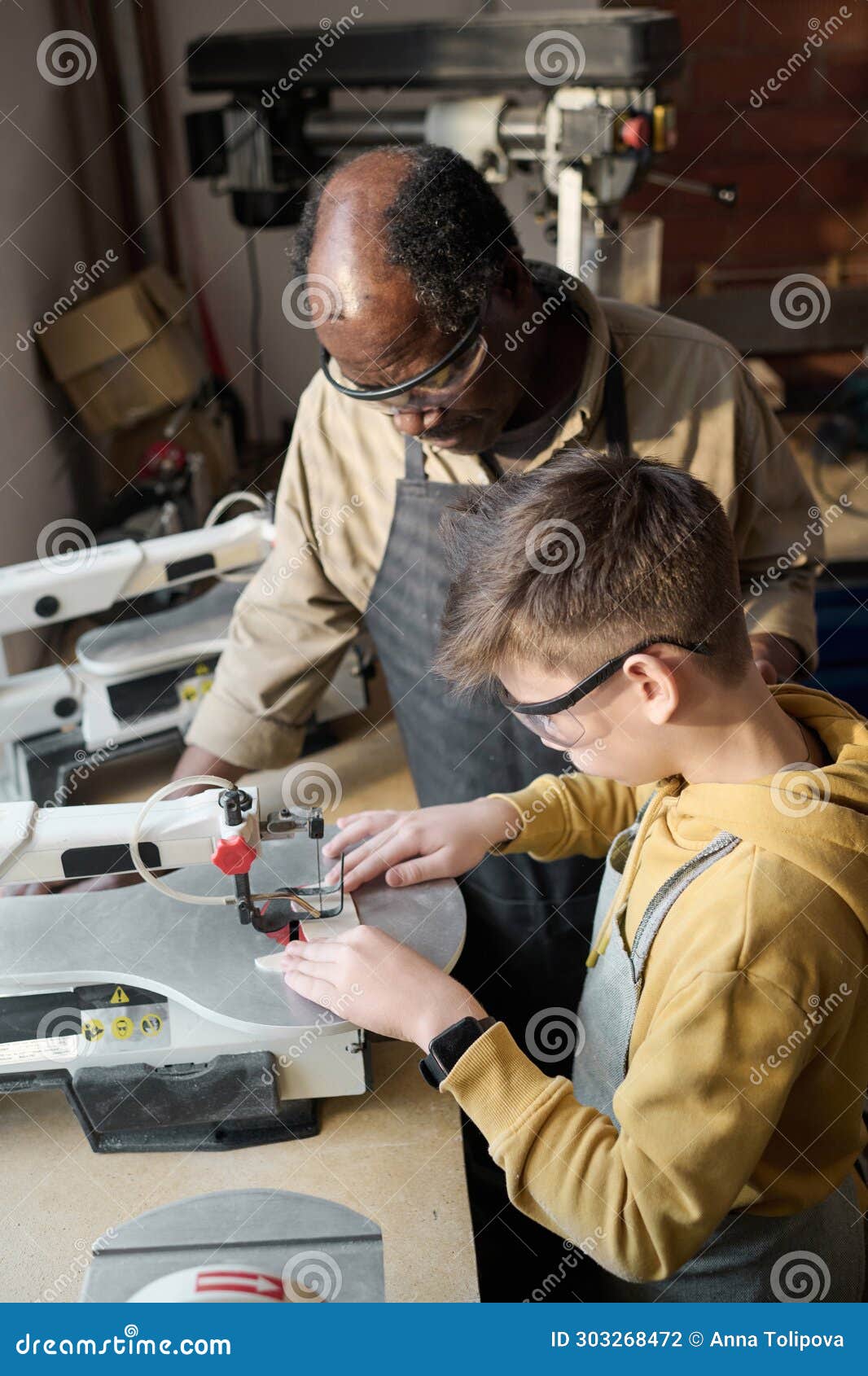 Boy Cutting Wood Using Machine Tools in Workshop with Master Helping ...