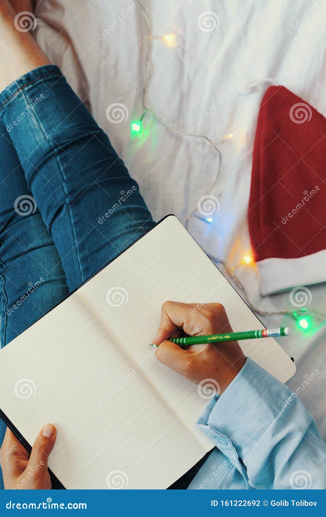High Angle View To Young Woman Lying In Bed And Writing With Pen On