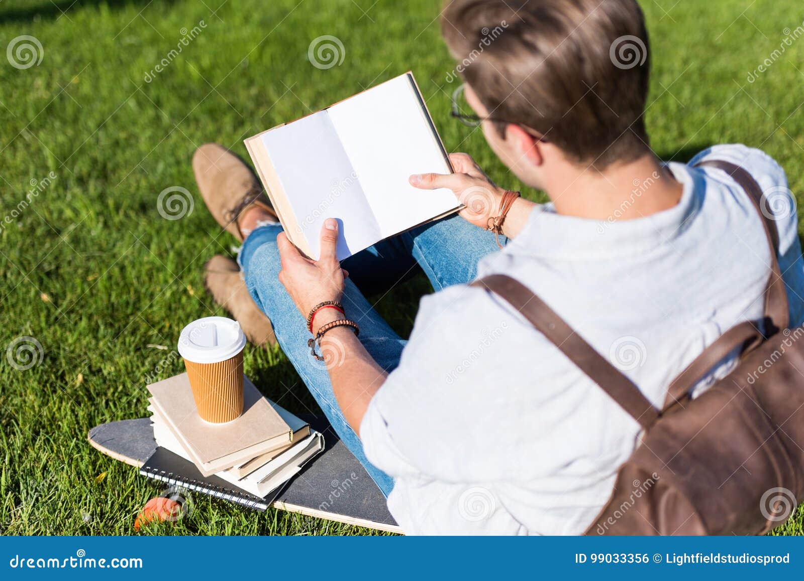 Young Man in Eyeglasses and Backpack Reading Book while Sitting on ...