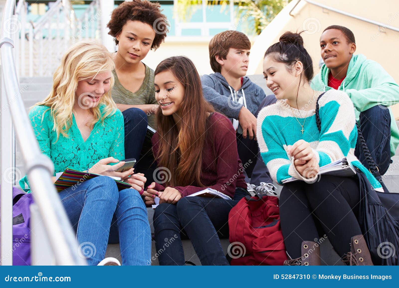 High School Students Sitting Outside Building with Phones Stock Photo ...