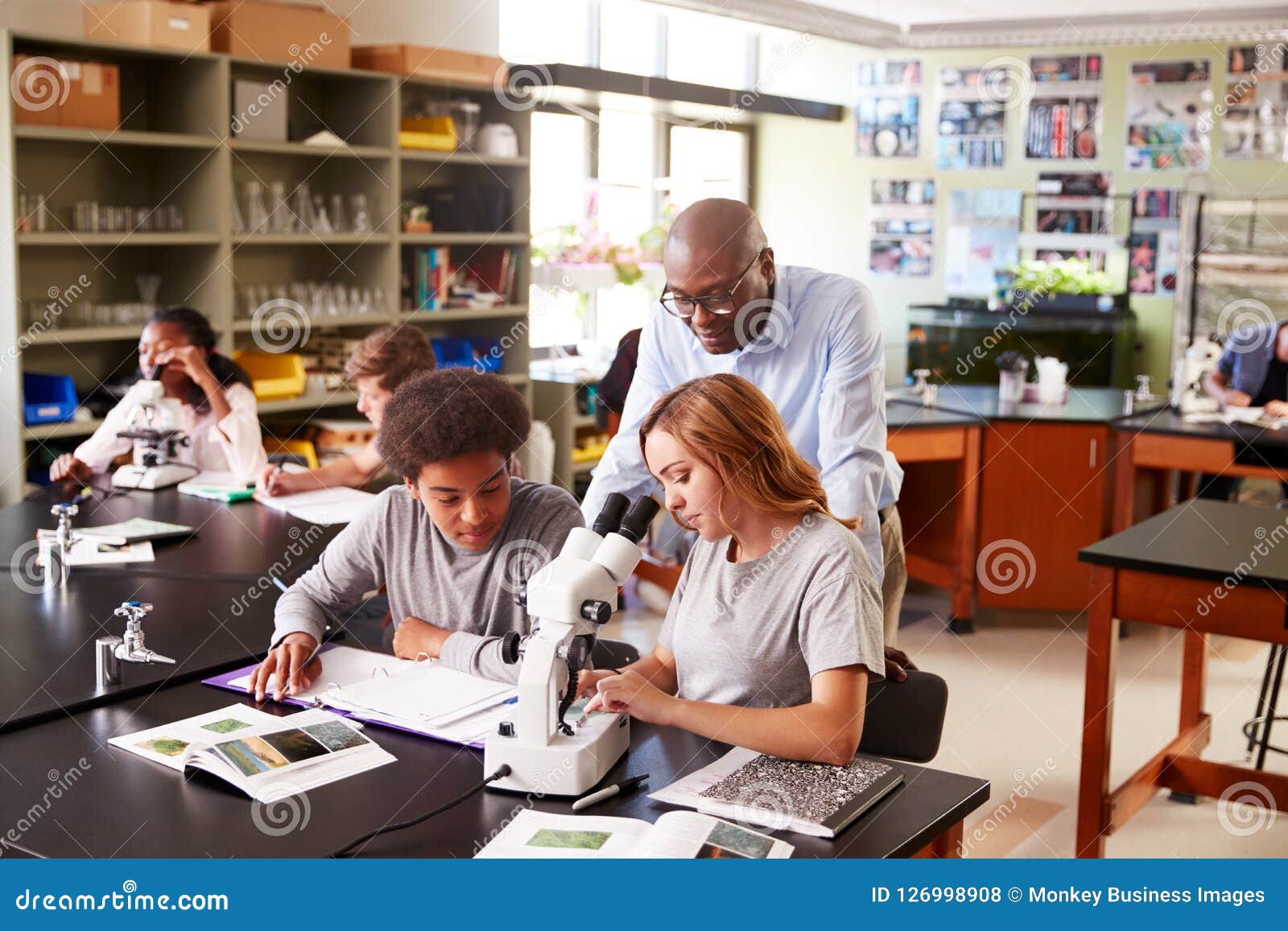 High School Students with Tutor Using Microscope in Biology Class Stock ...