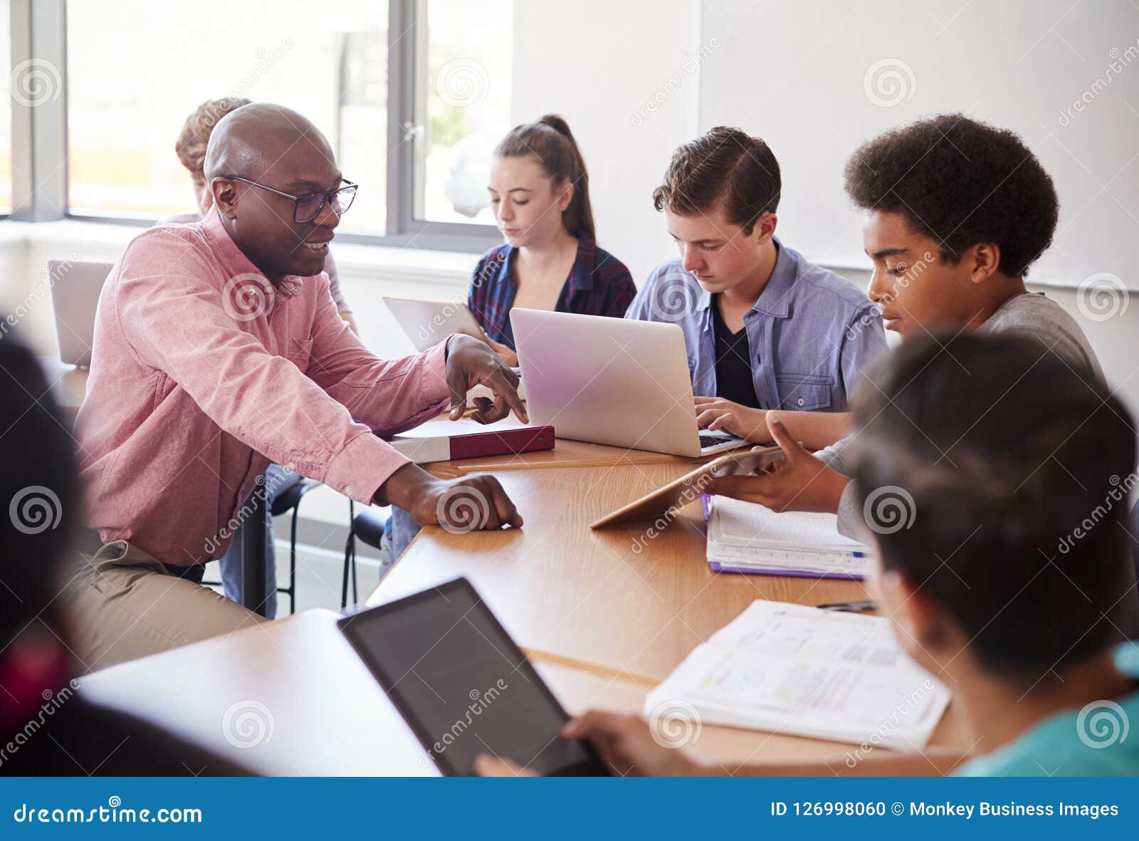 High School Teacher Talking To Pupils Using Digital Devices in ...