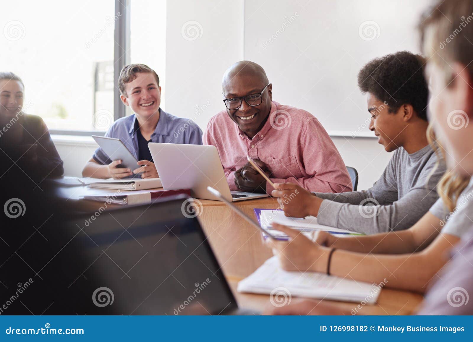 High School Teacher Talking To Pupils Using Digital Devices in ...