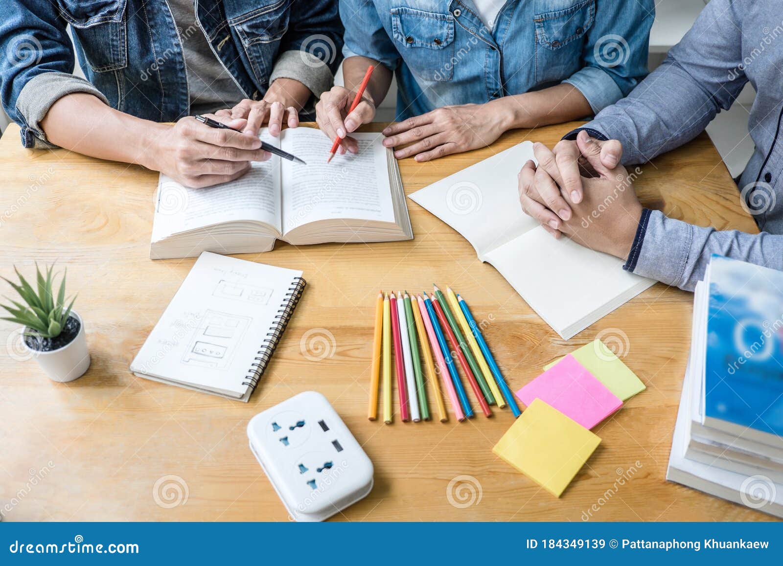 High School Tutor or College Student Group Sitting at Desk in Library ...