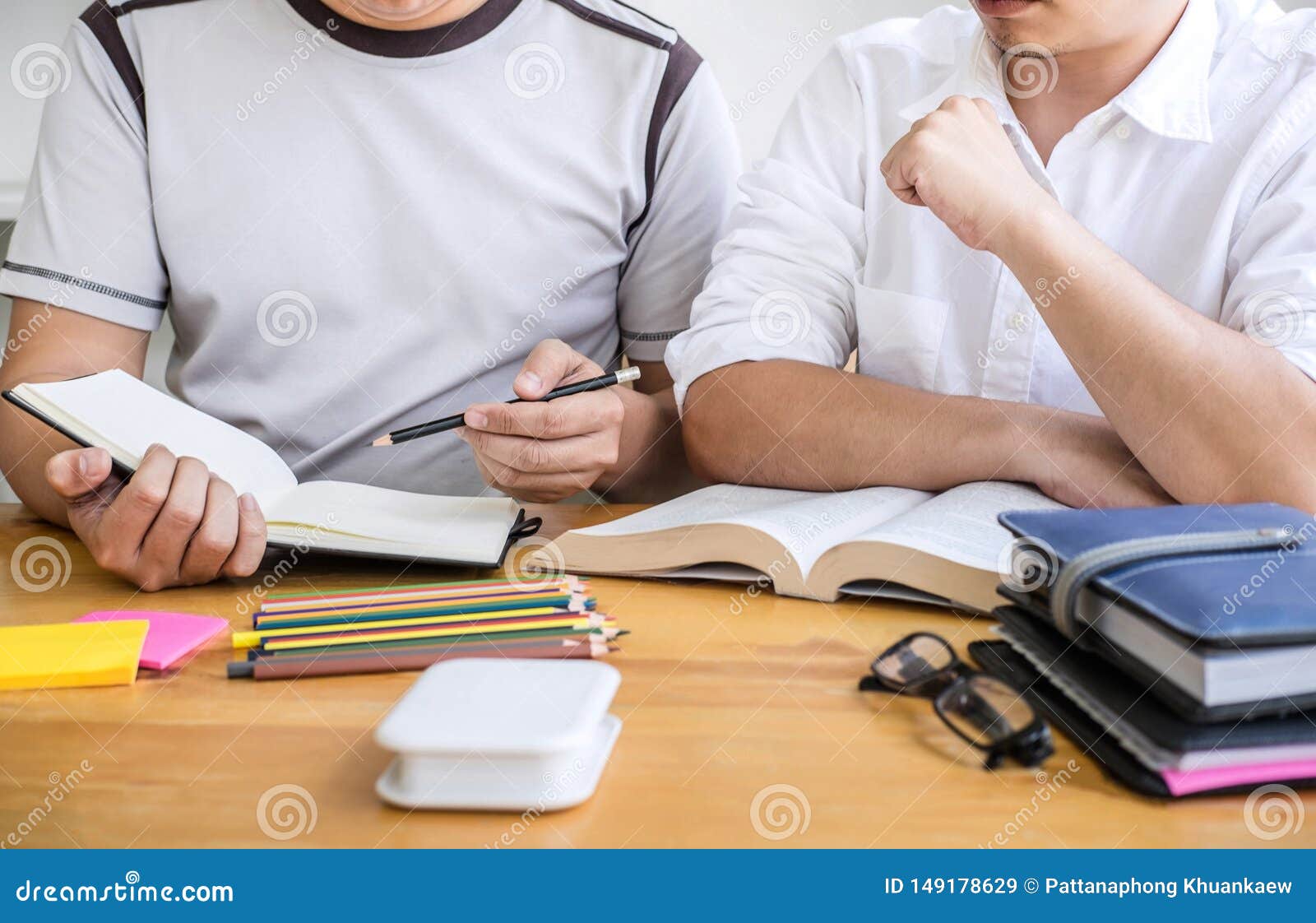 High School Tutor or College Student Group Sitting at Desk in Library ...