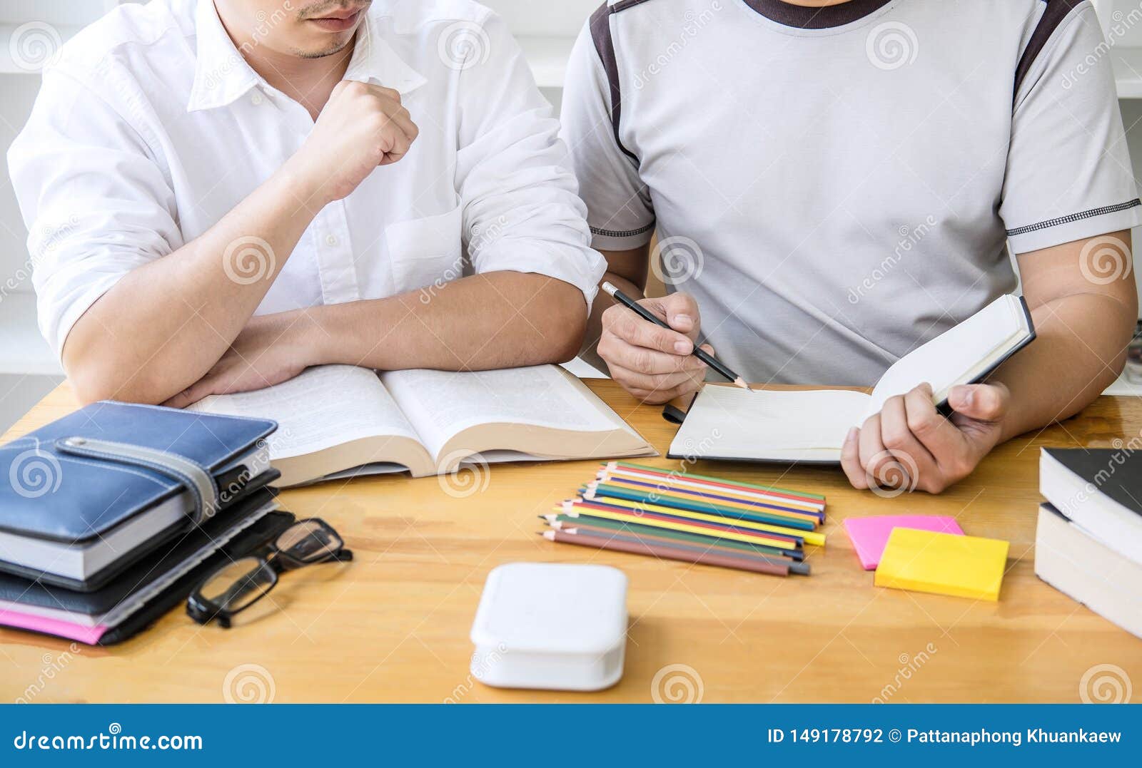 High School Tutor or College Student Group Sitting at Desk in Library ...