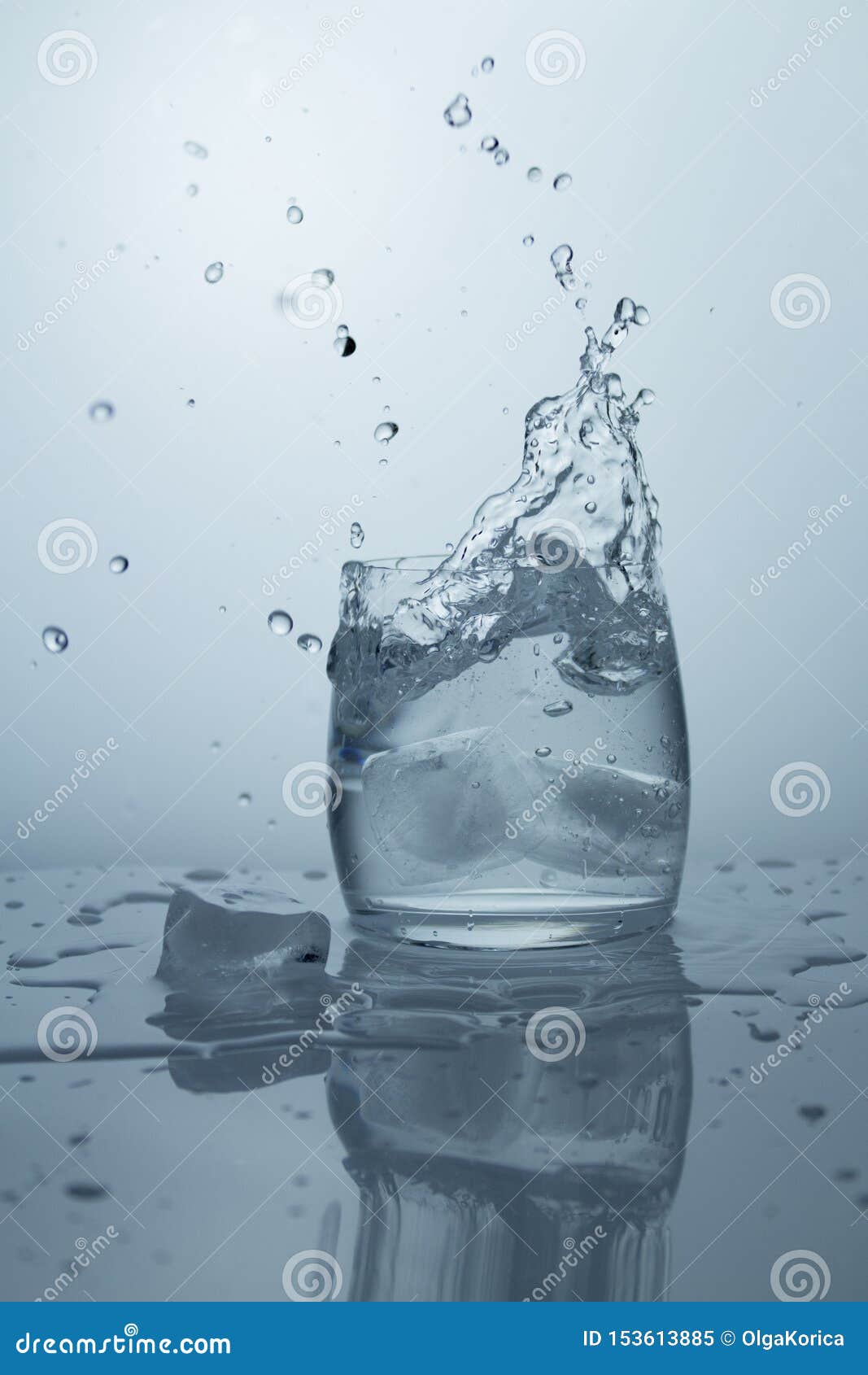 High Splash with Splashes of Pure Cold Water. Ice Falls into a Glass ...