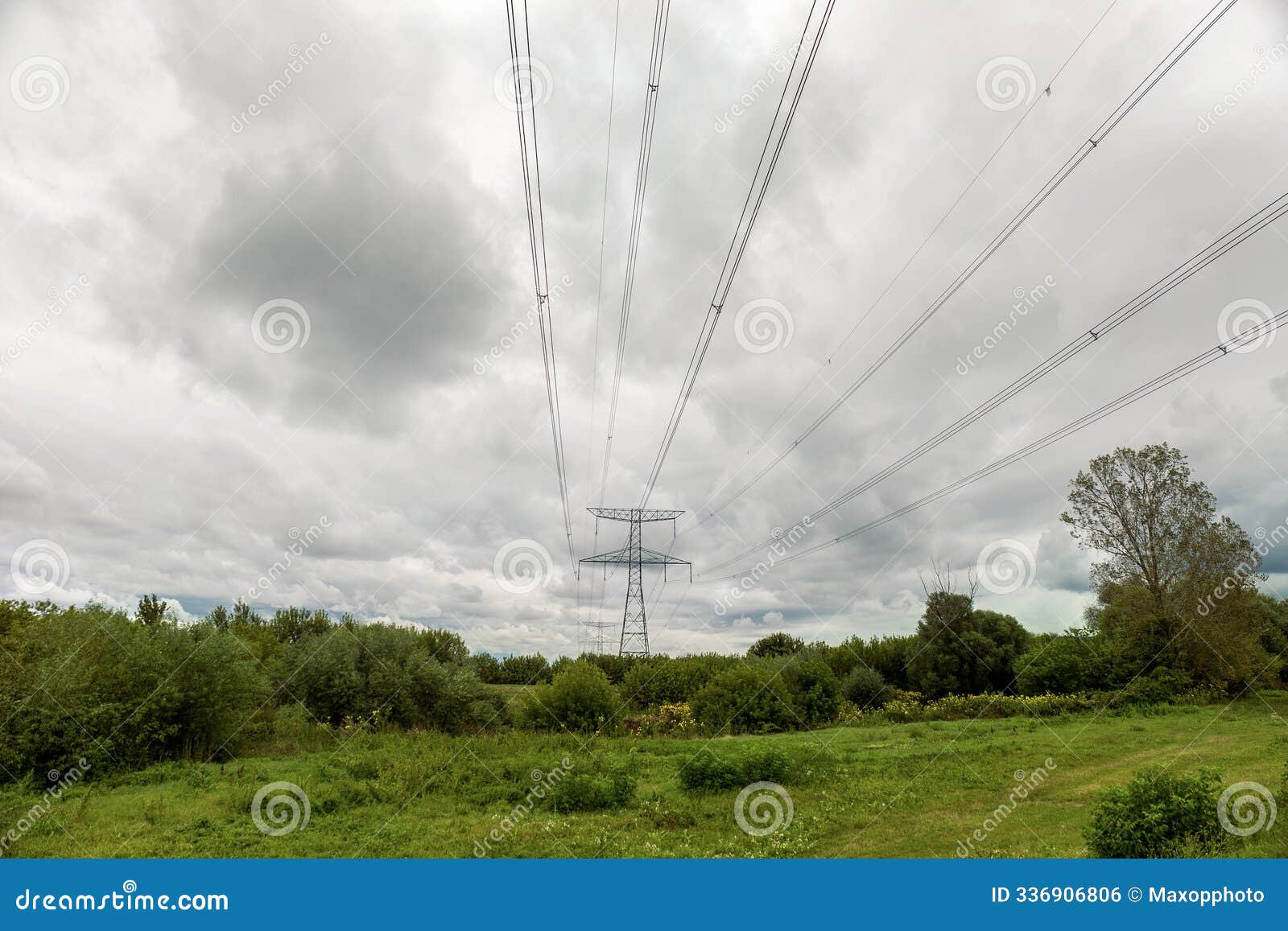 High Voltage Overhead Power Line. Green Meadow with a Cloudy Sky Stock ...