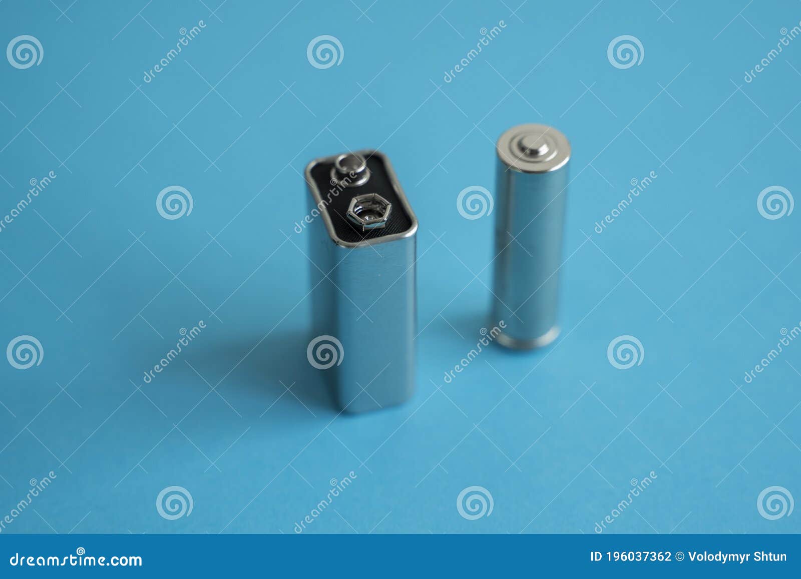 High Voltage Volt 9V Battery and Alkaline AA Battery on a Blue ...