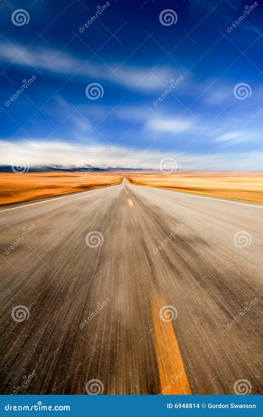 A Highway Receding To Perspective Toward A Mountain Range In A Desert ...