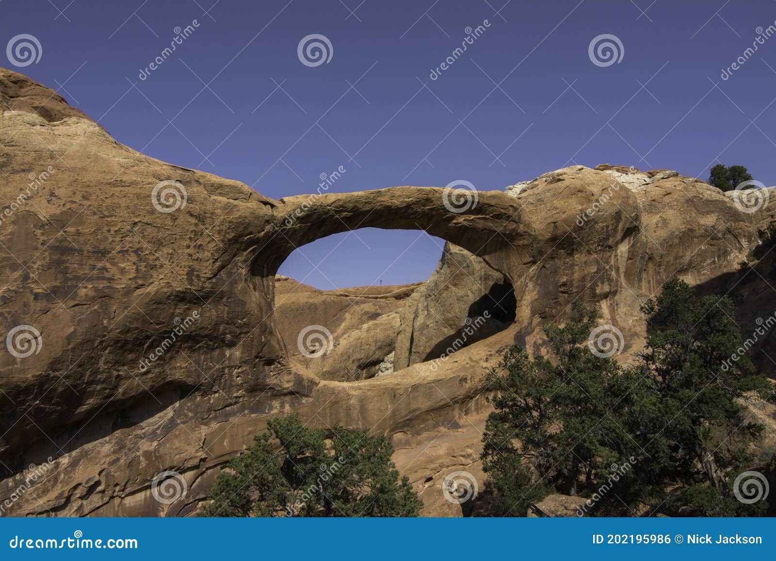 A Hiker is Visible through a Large Sandstone Arch Formation Stock Photo ...